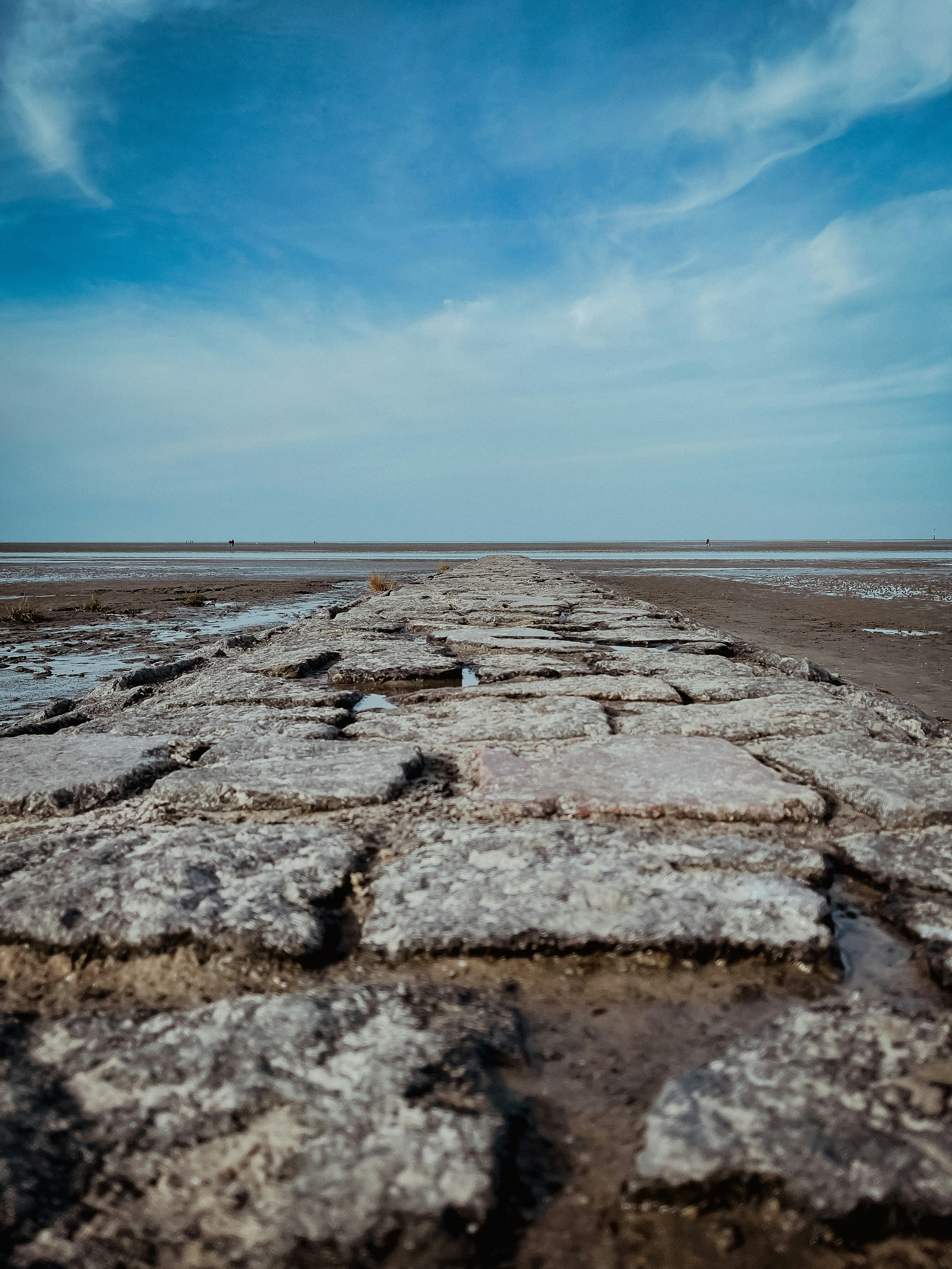 A long brick wall sitting on top of a sandy beach photo – Free Walkway ...