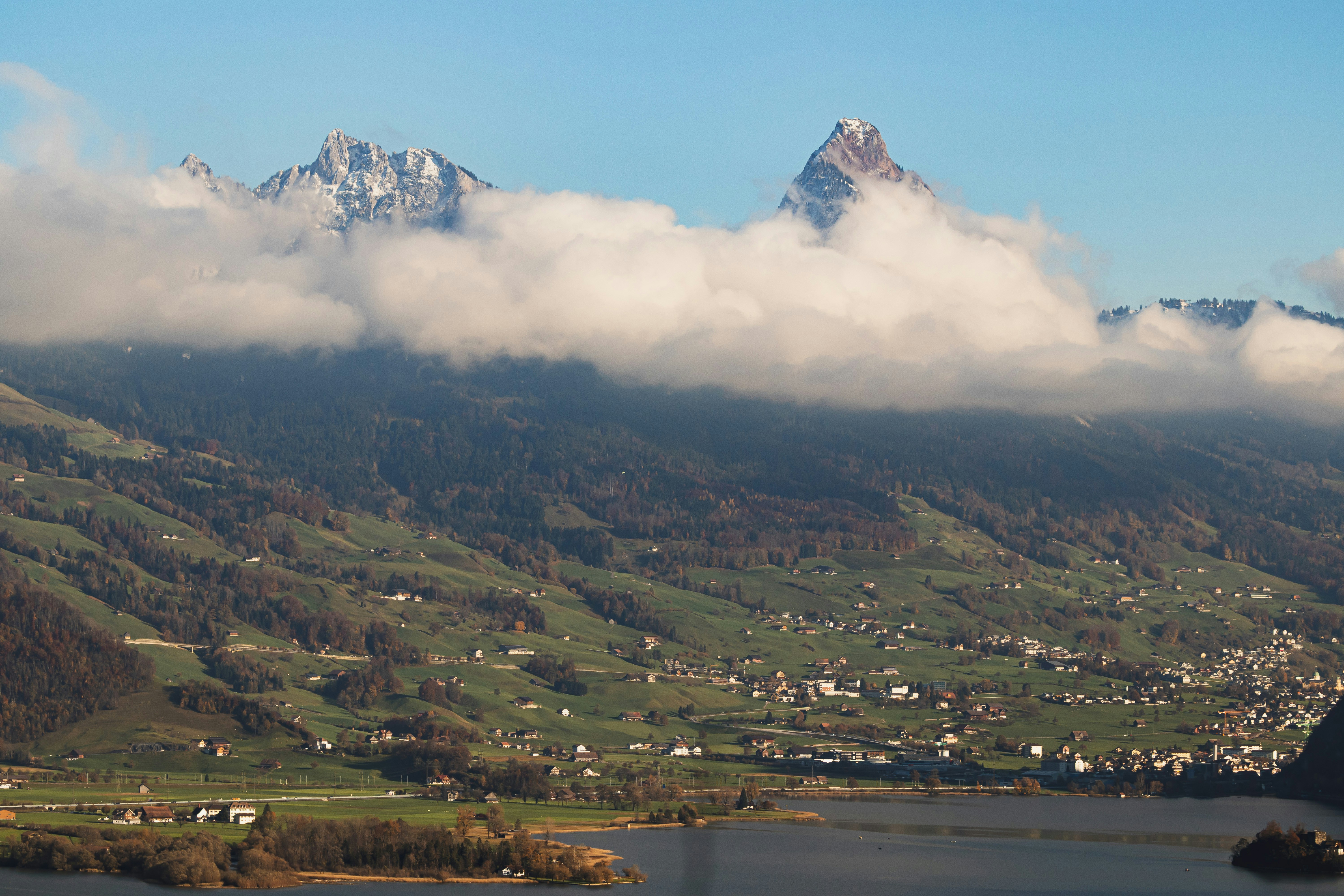 Twin Alpine Peaks Piercing the Cloud Veil Over a Patchwork Valley.