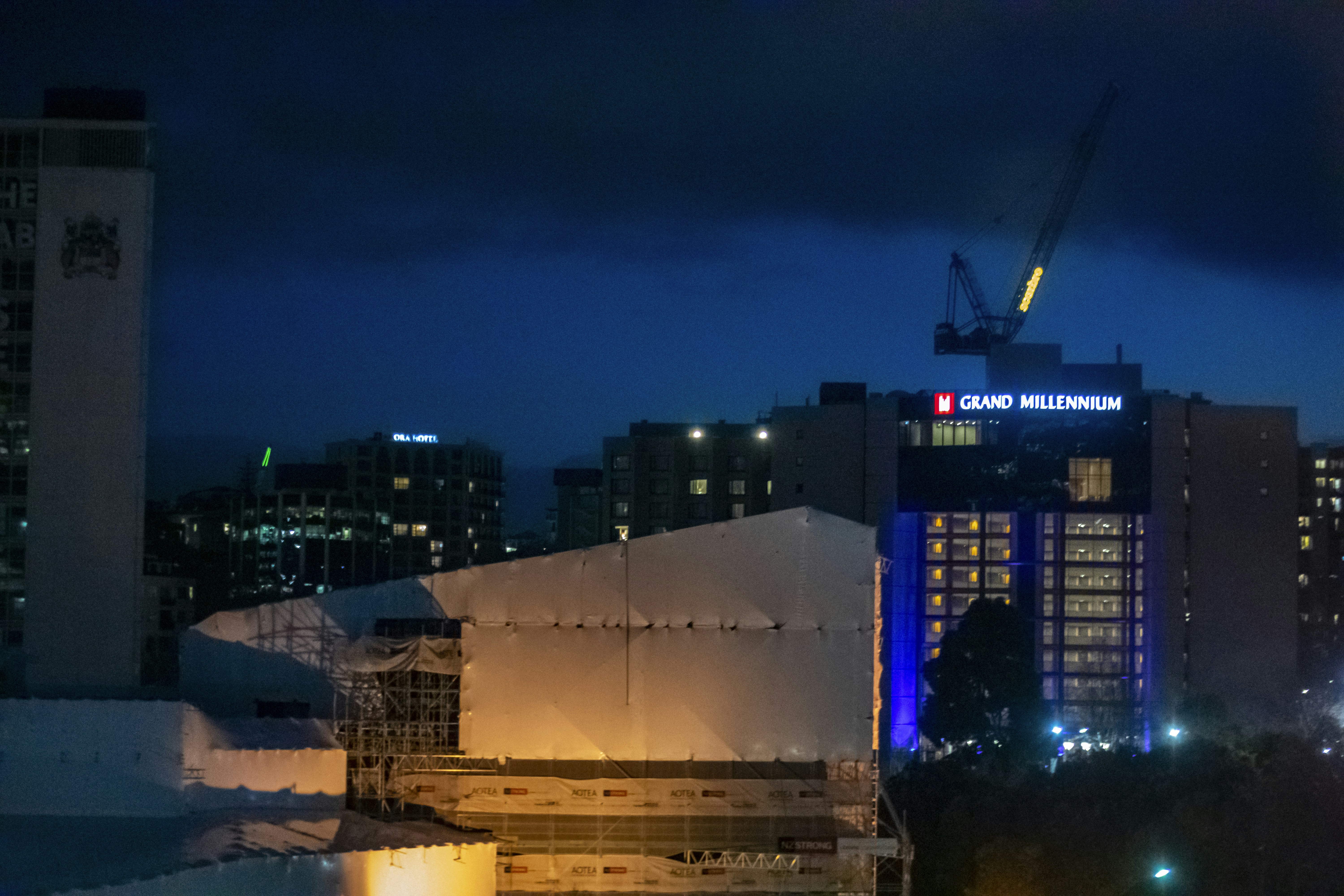 Blue Neon Skyline Framing a Snow-White Construction Facade by Grand Millennium