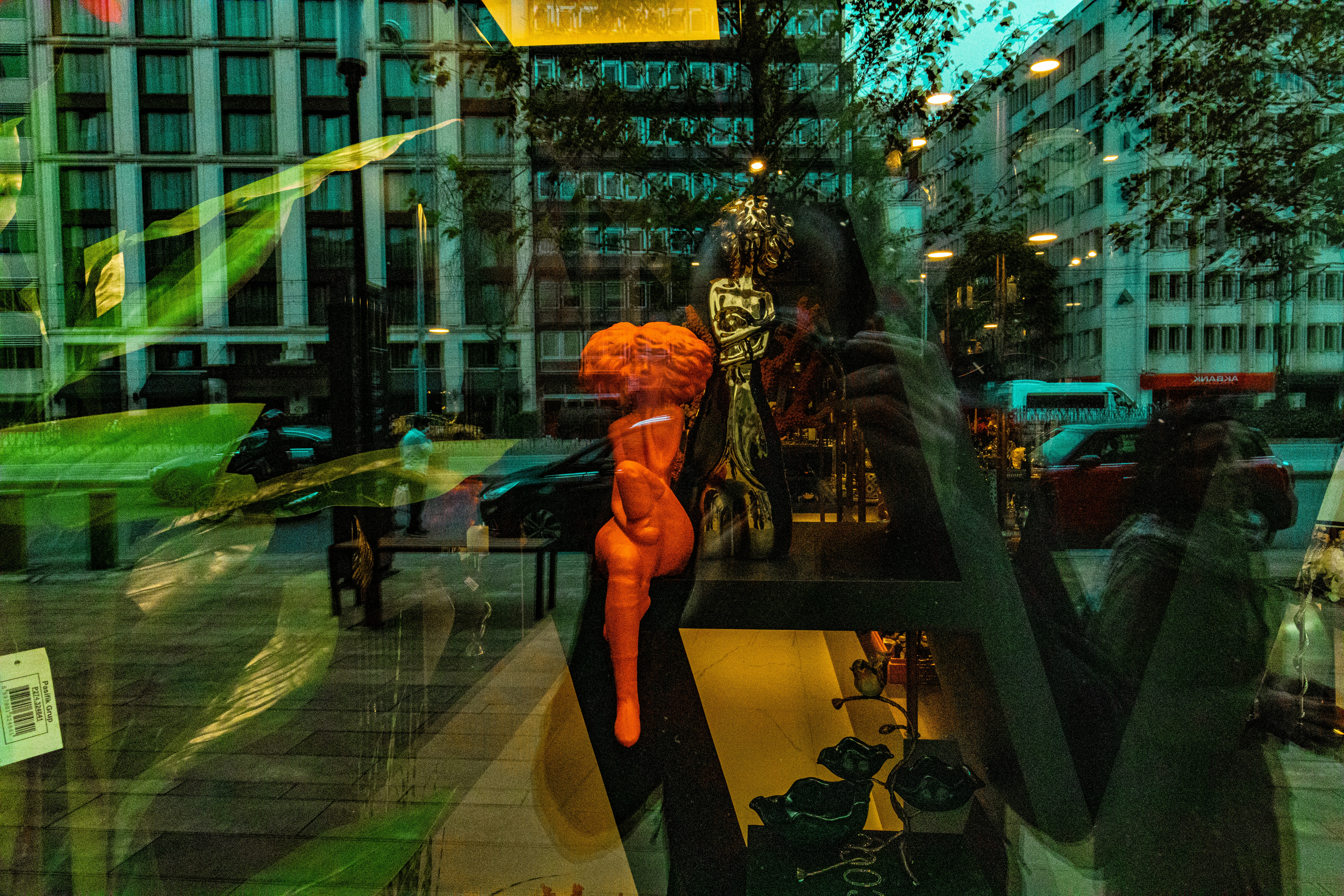 Between Glass and Street: An Orange Figure Framed by Bold Letters