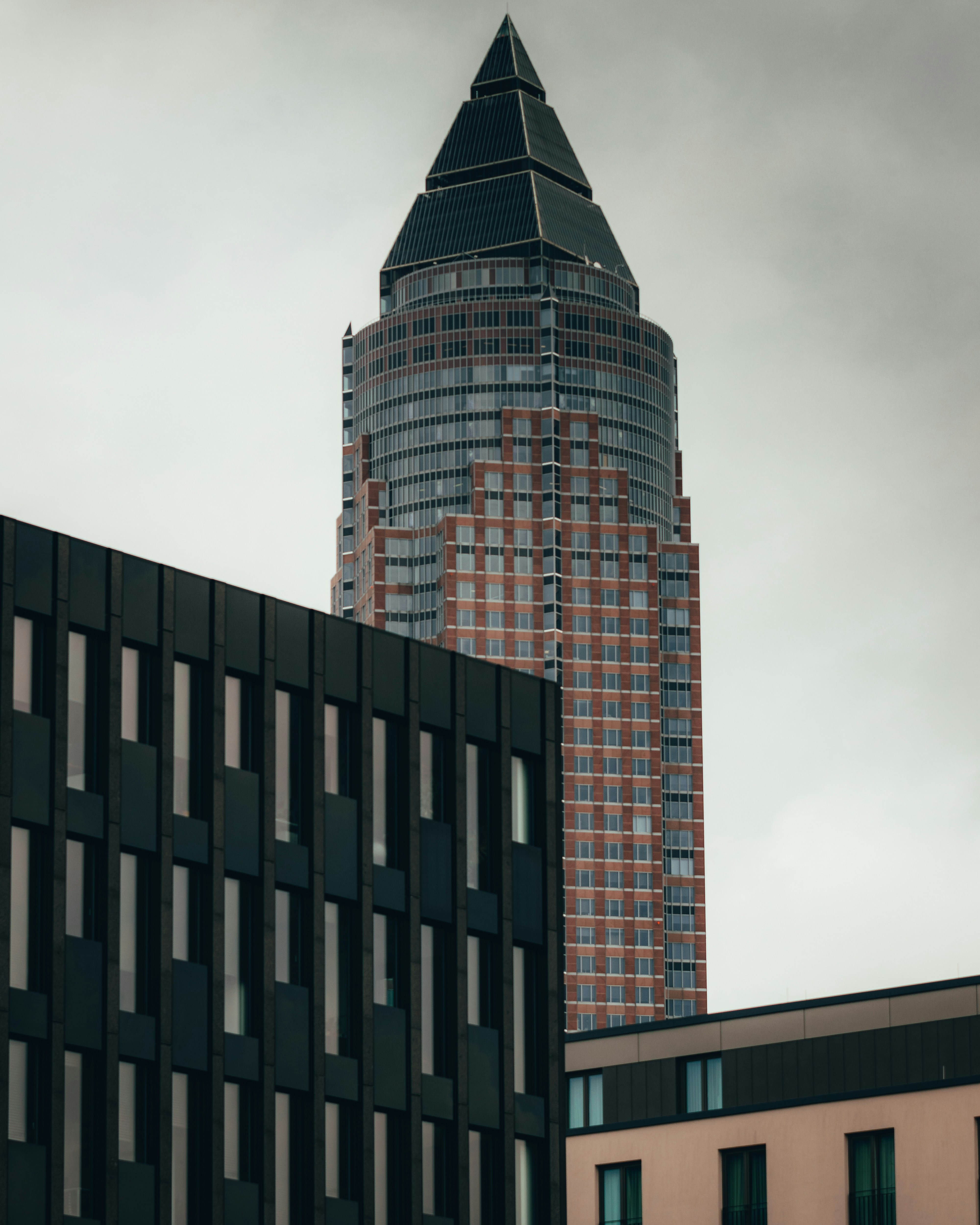 A striking architectural composition featuring a towering skyscraper amidst contemporary buildings, set against a moody sky.