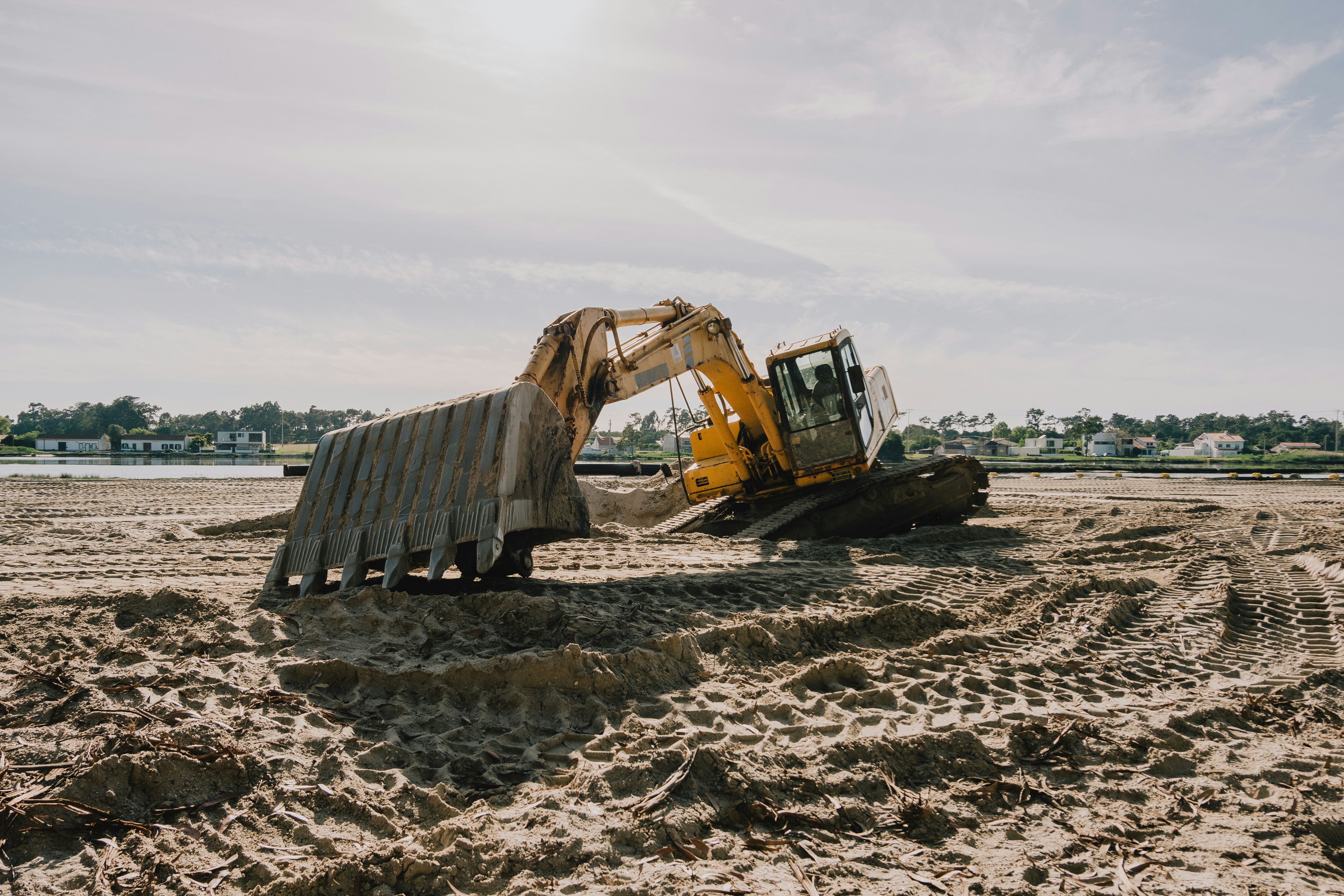 a bulldozer digging in the sand on a beach