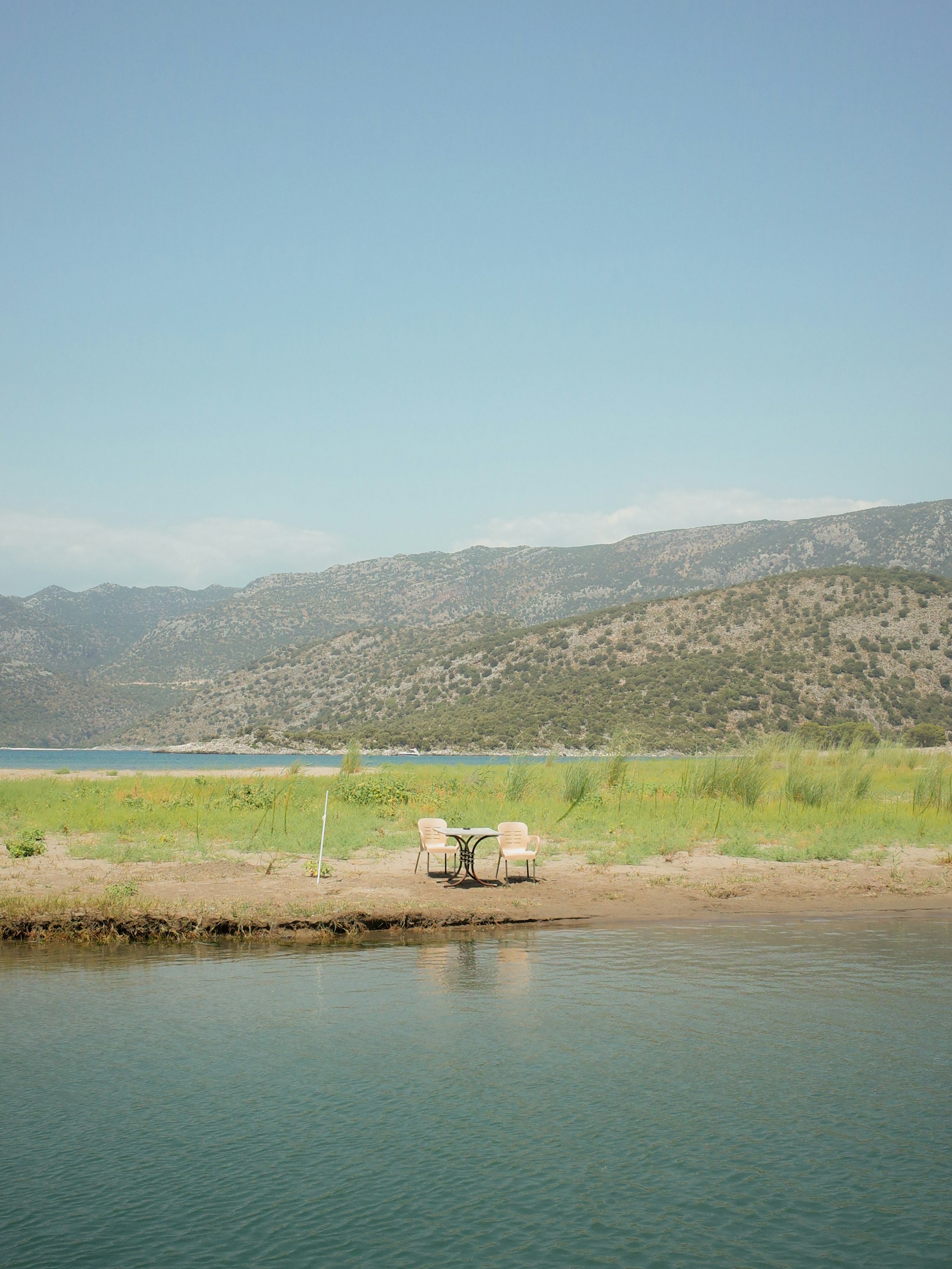 Chairs and table sit by the water's edge.