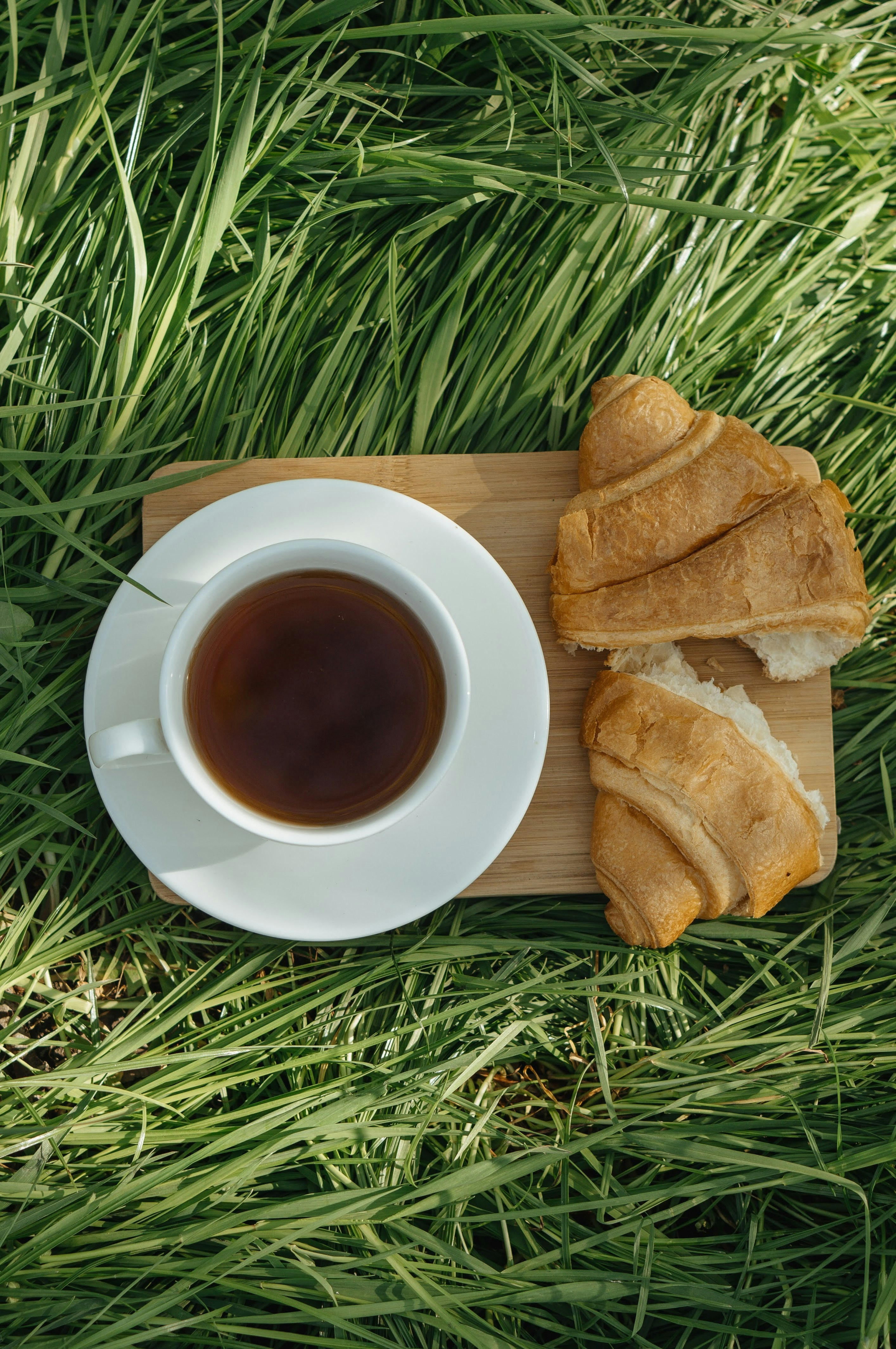 Grassbound Morning: Coffee Cup and Croissants on a Rustic Board