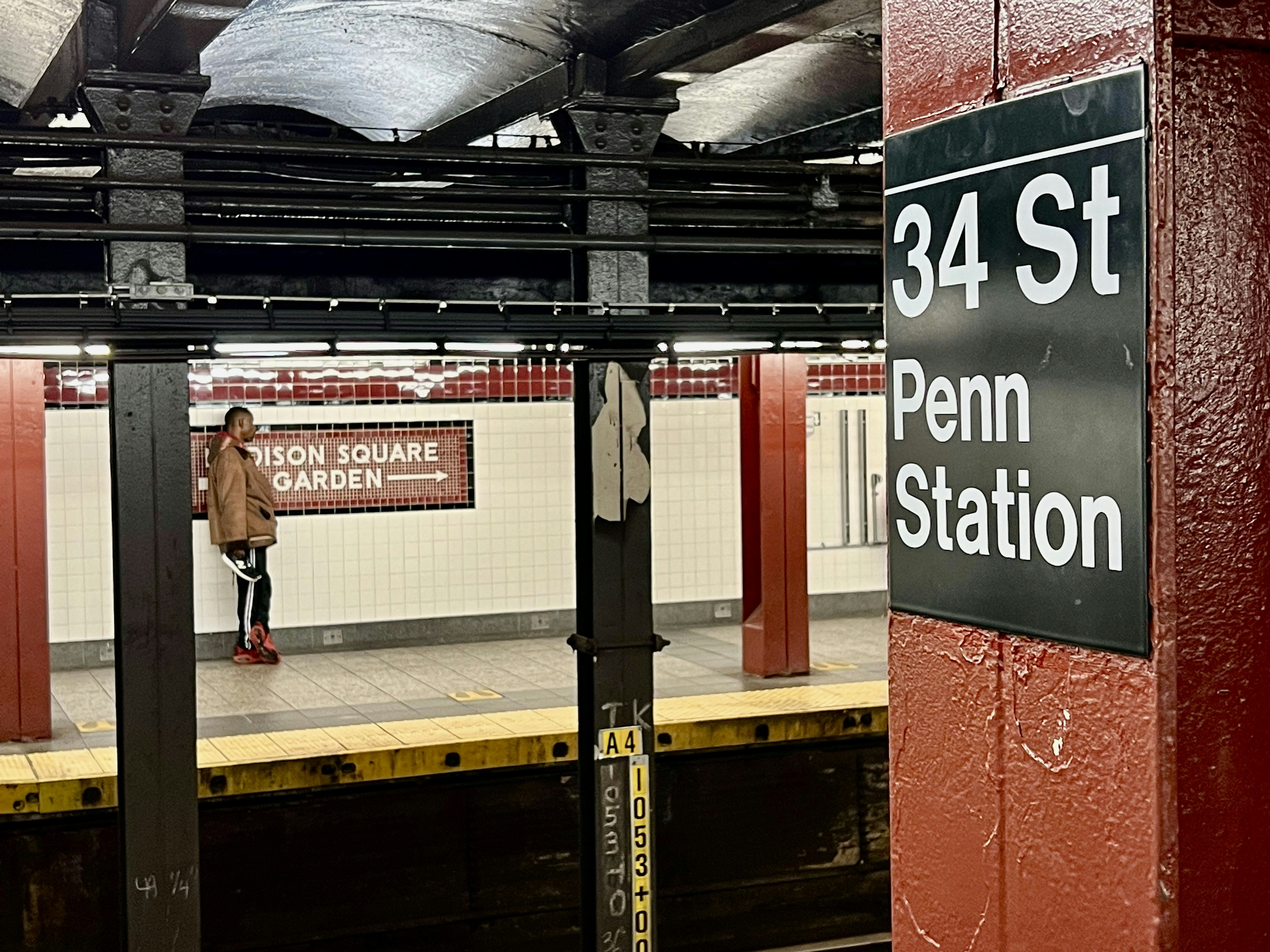 A person standing on a train platform next to a sign photo – Free Penn ...