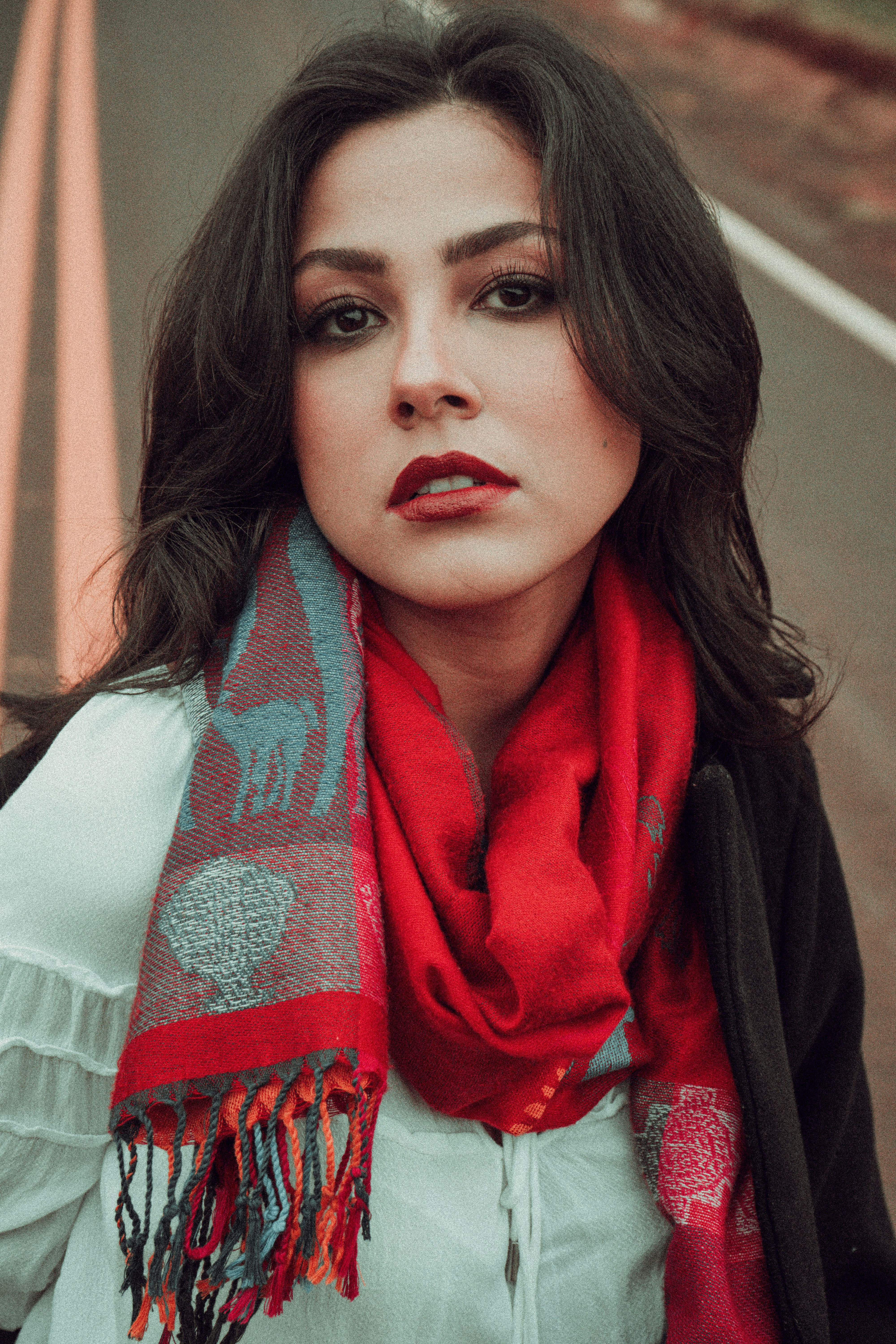 Crimson scarf frames a poised gaze on a city-edge portrait