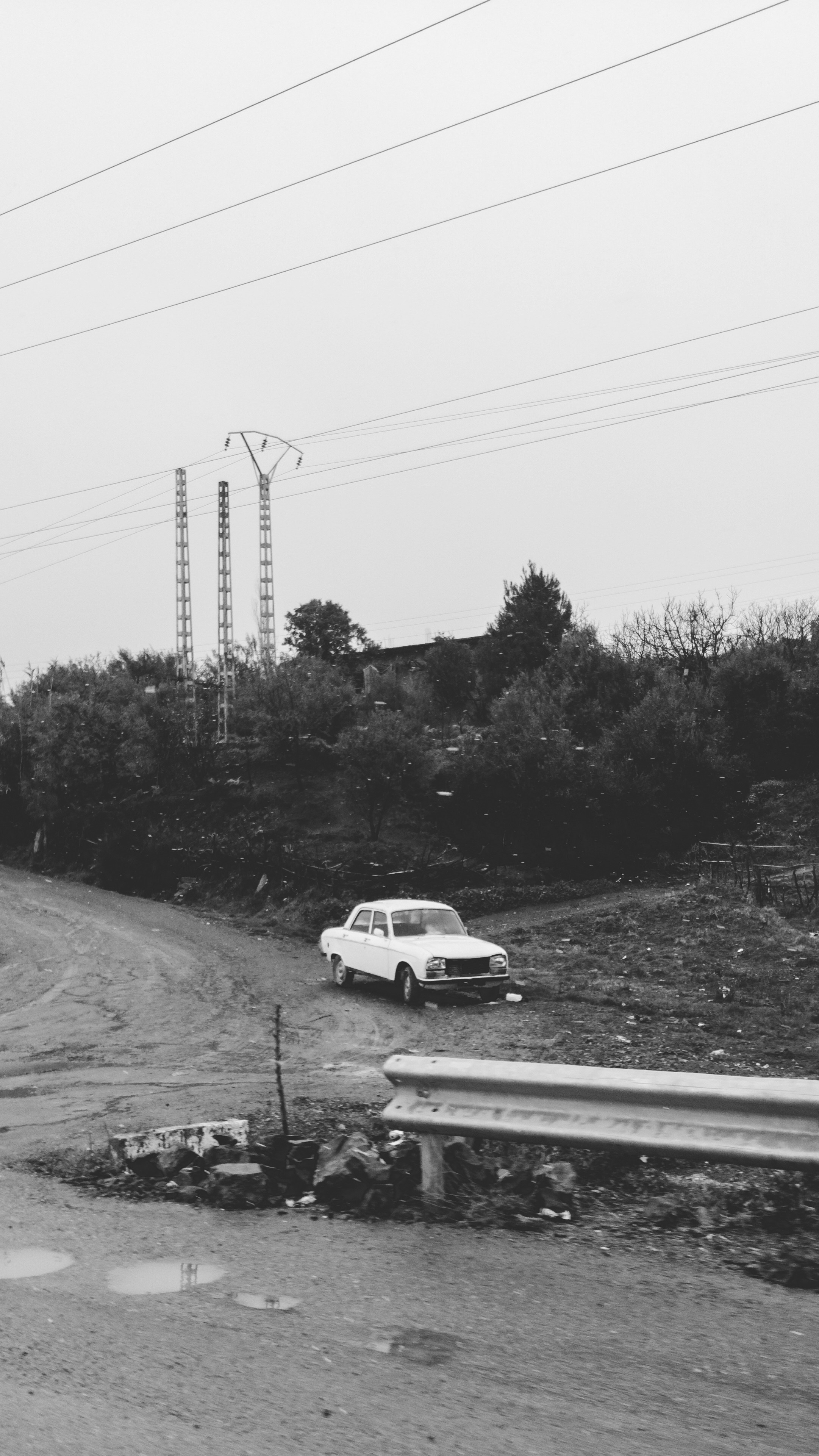 Gravel Crossroads: A Vintage Sedan Beneath Looming Power Lines