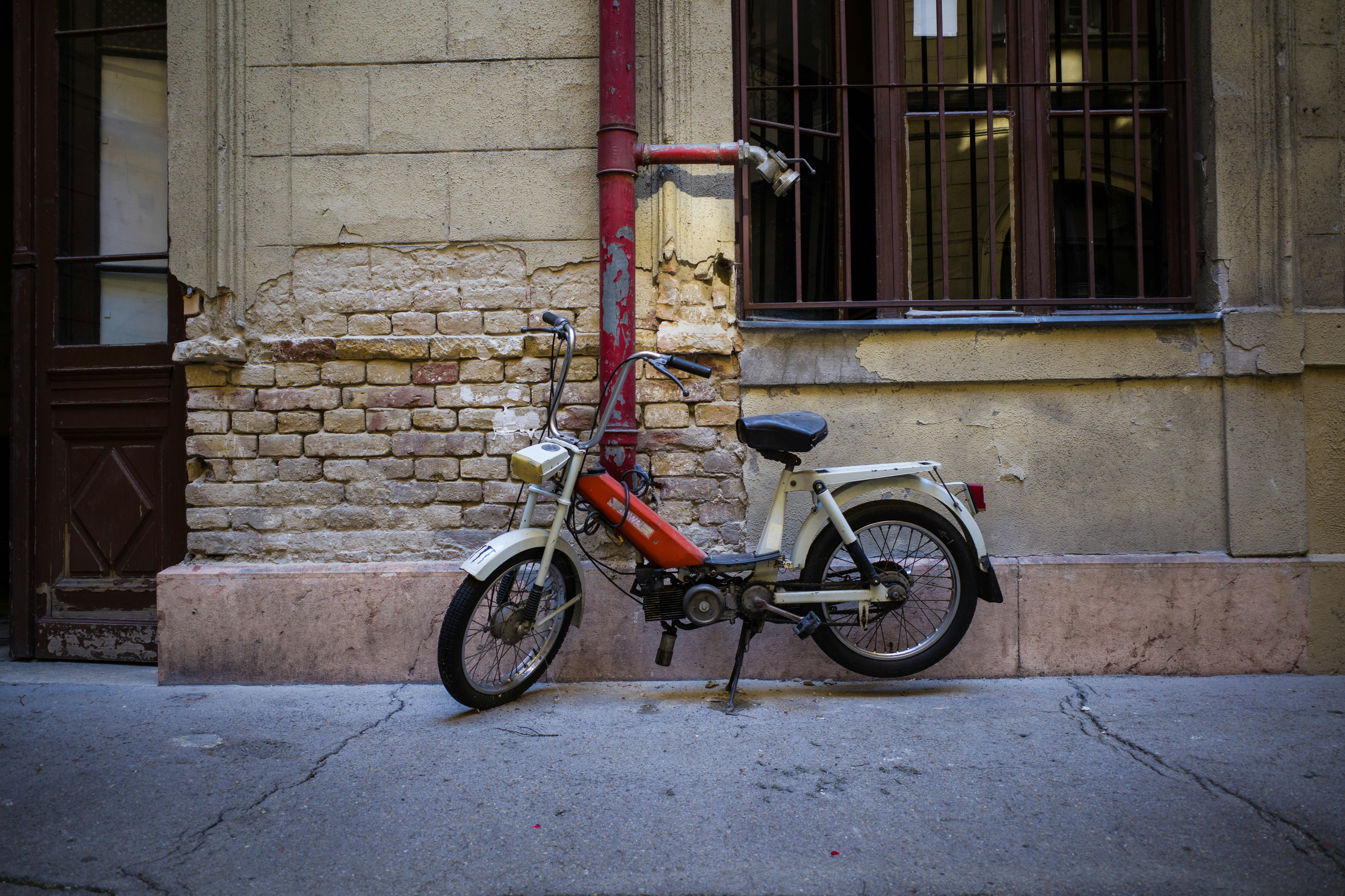Old Red Moped Resting Against a Weathered Facade