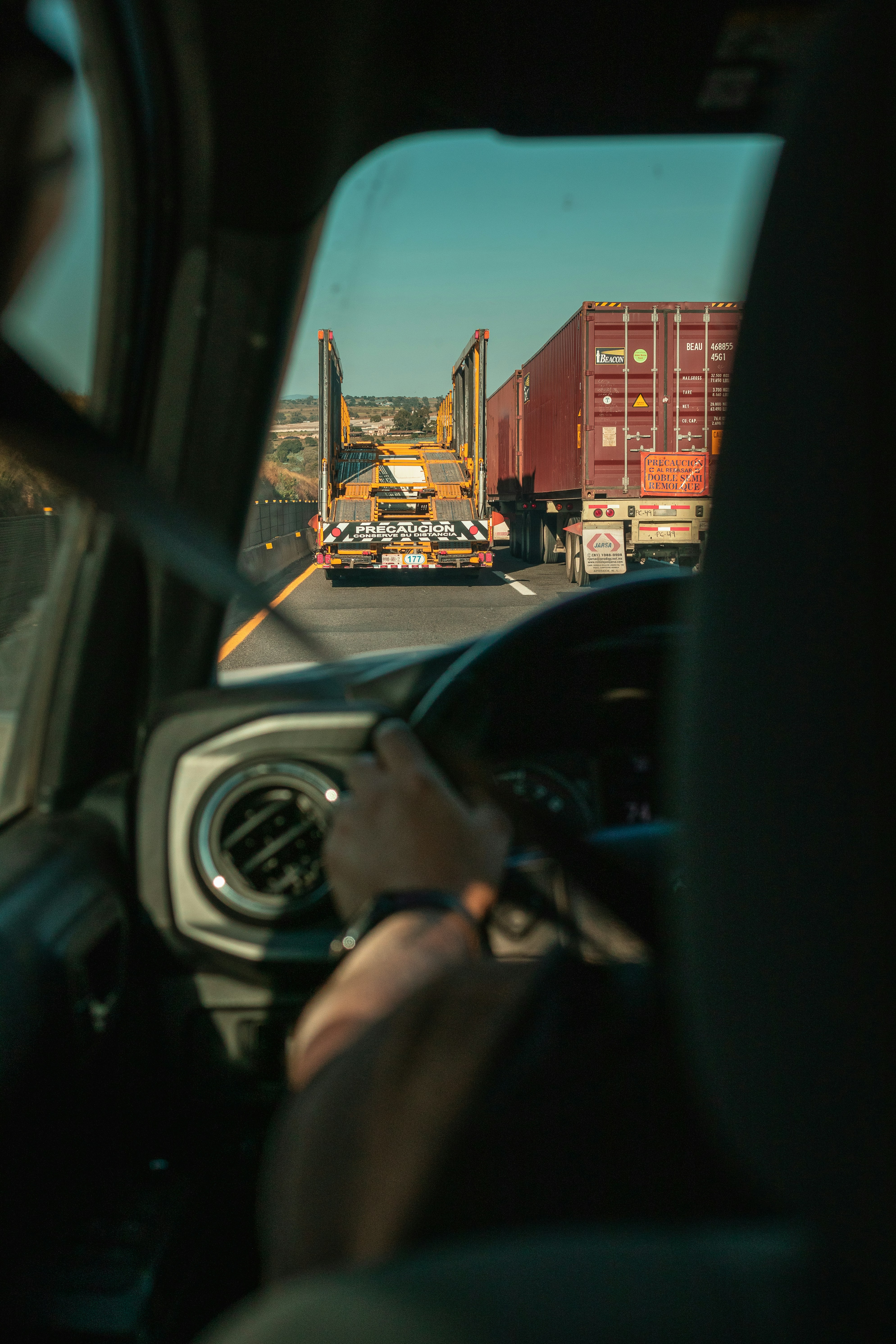 Cab View on the Highway: A Yellow Tow Rig Aligns with a Red Container Truck