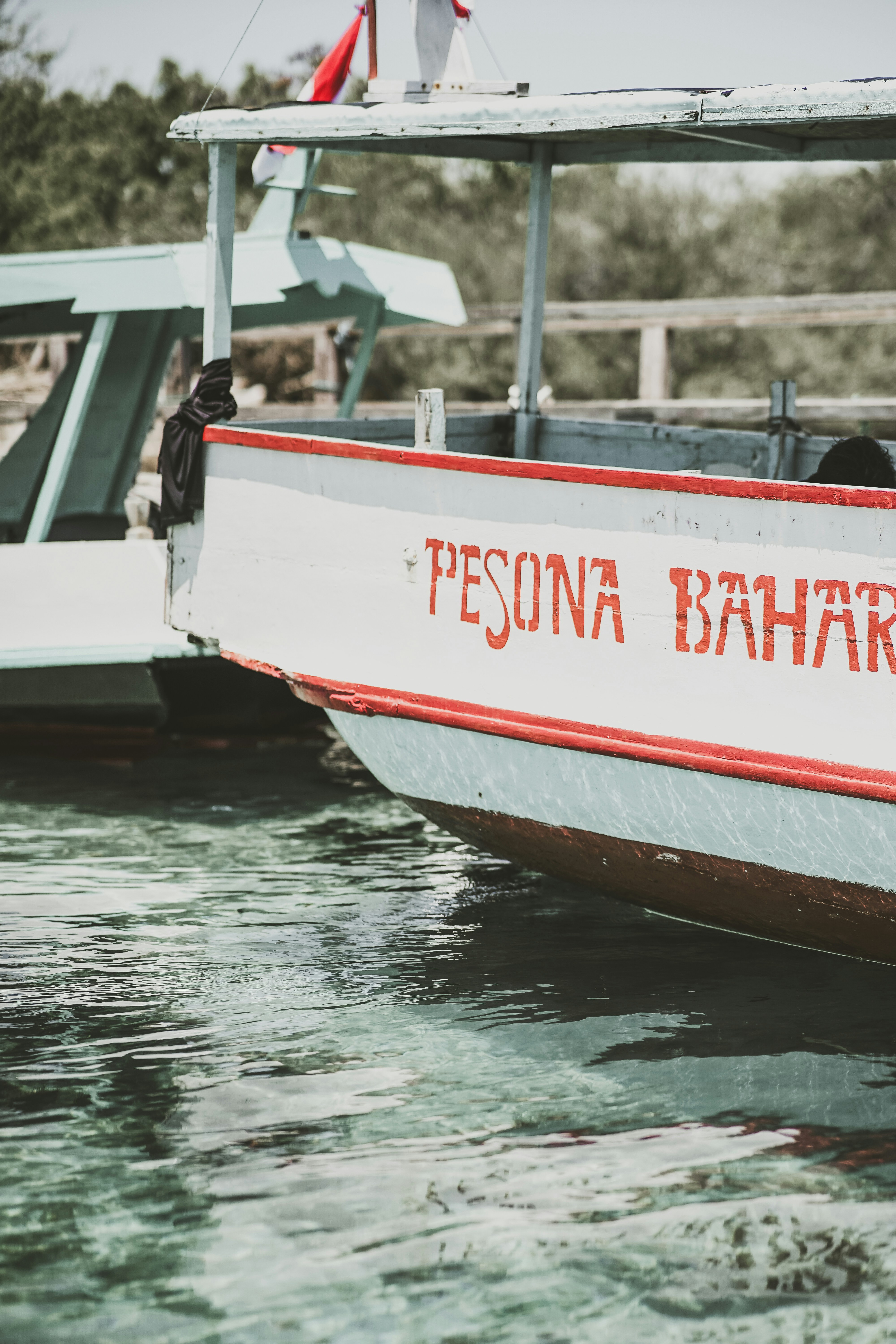 Bold Red Letters on Weathered Hulls by a Quiet Shore