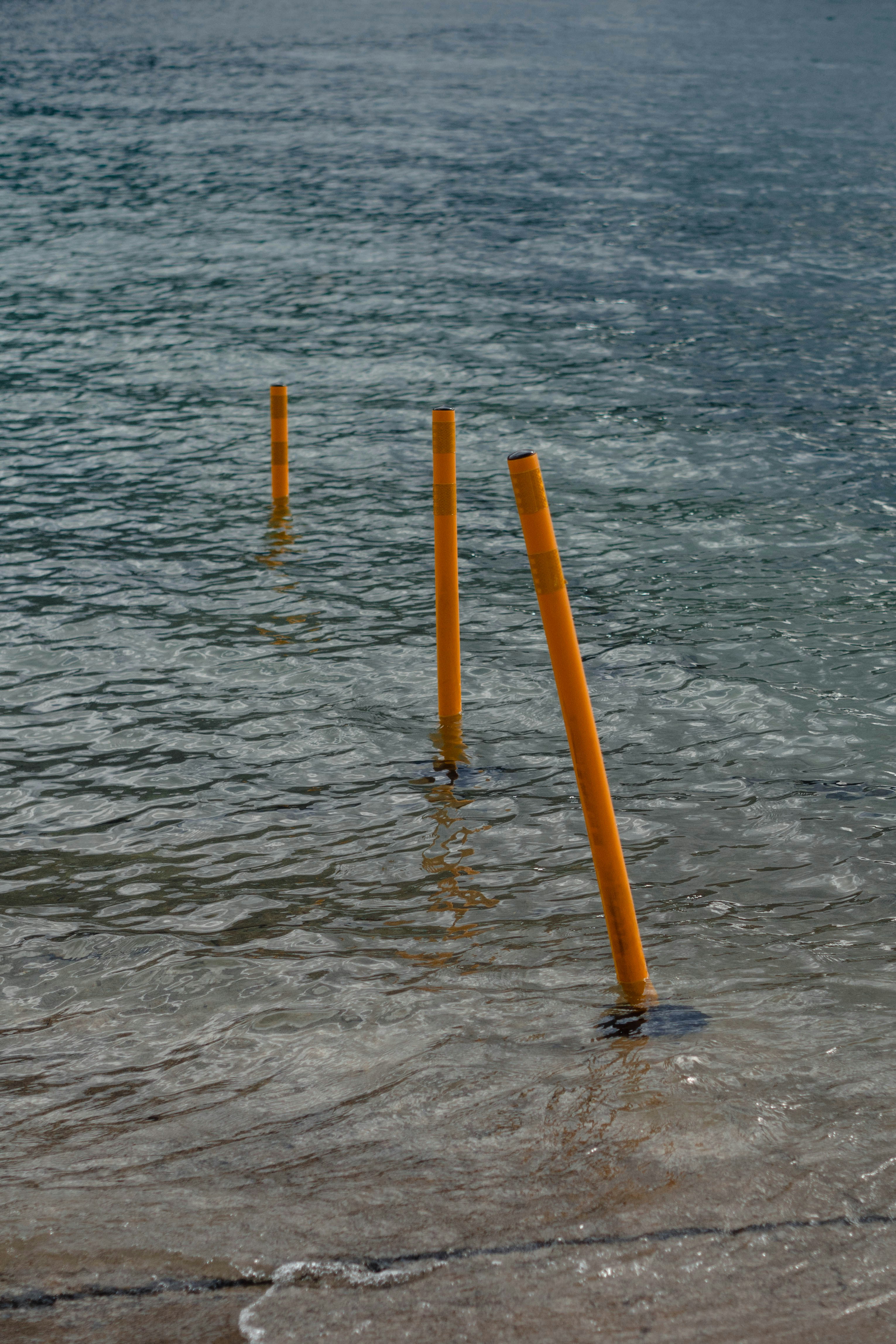 three orange poles sticking out of the water