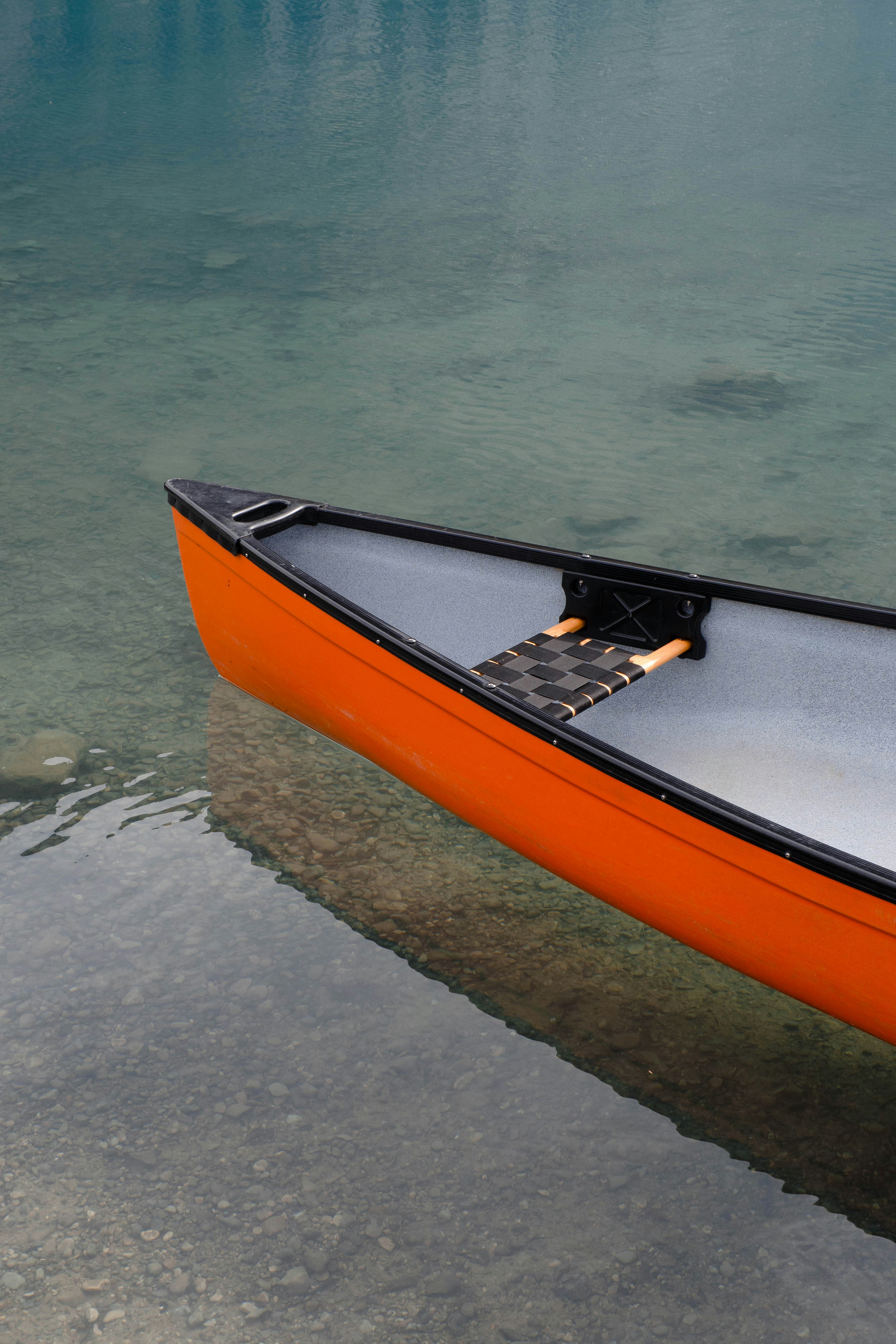 A small orange boat floating on top of a lake photo – Free Canoe Image ...