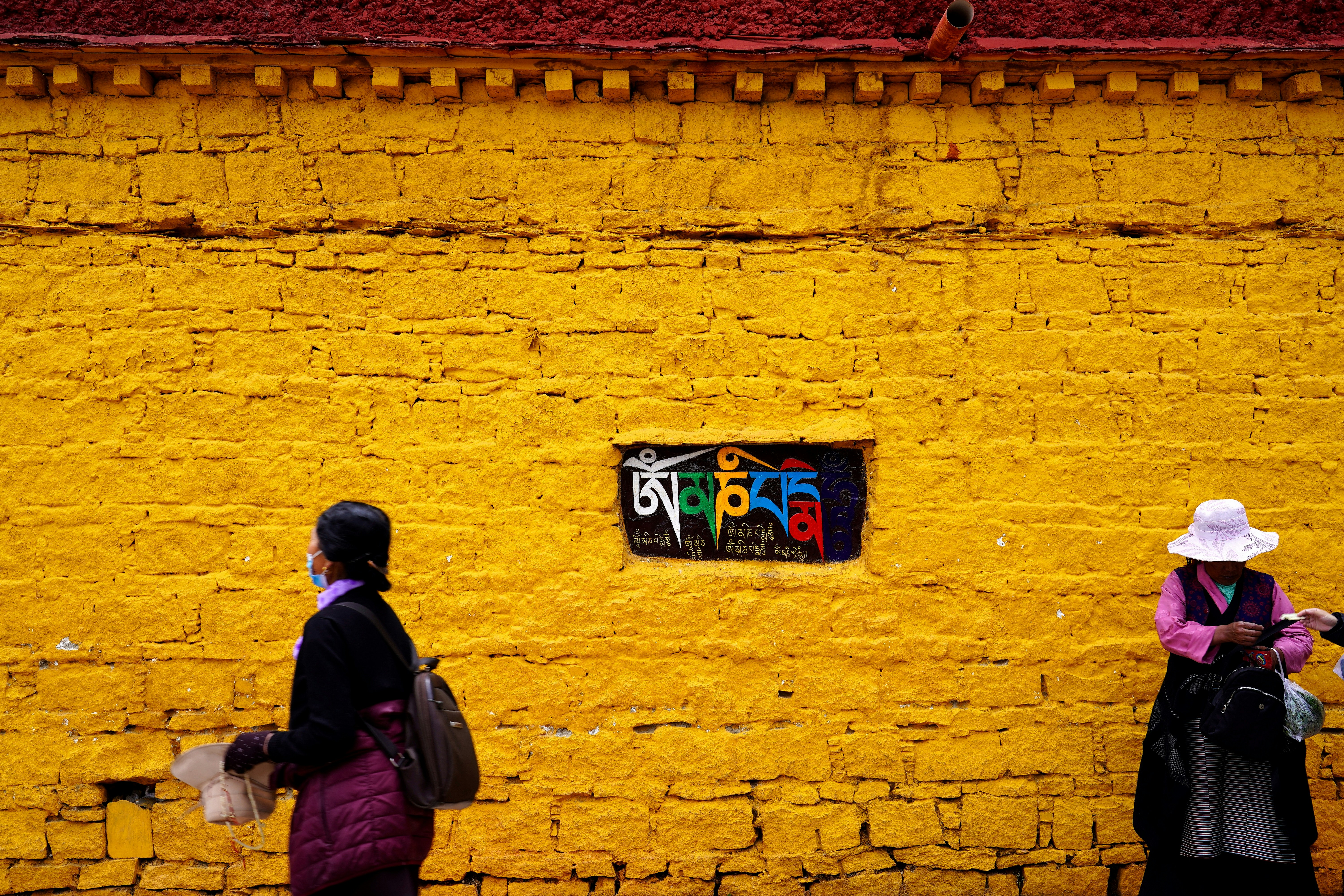 Ochre Wall Portrait: Center Sign Framed by Two Masked Passersby