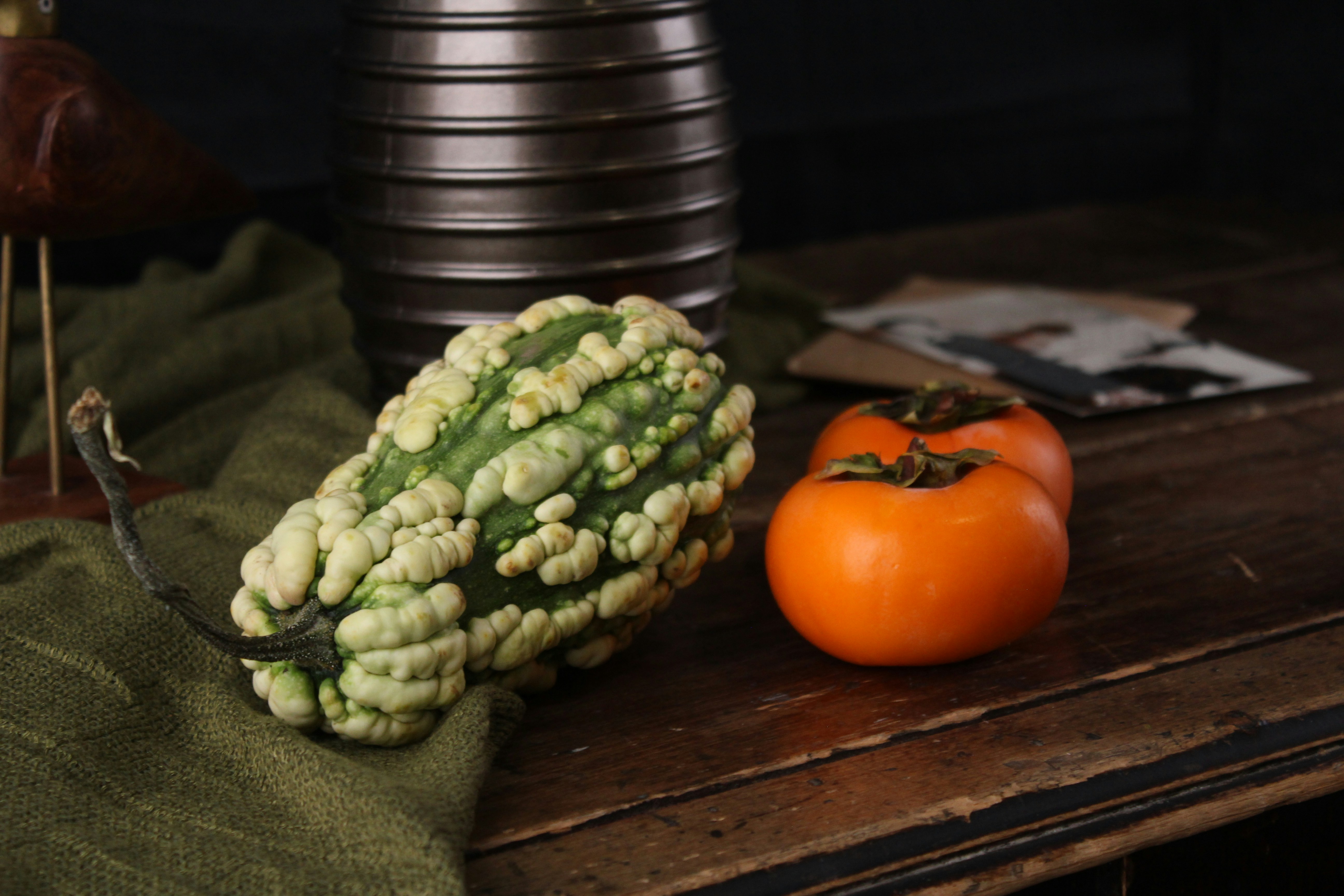 Weathered Table Still Life: Bitter Melon and Orange Tomato in Warm Light