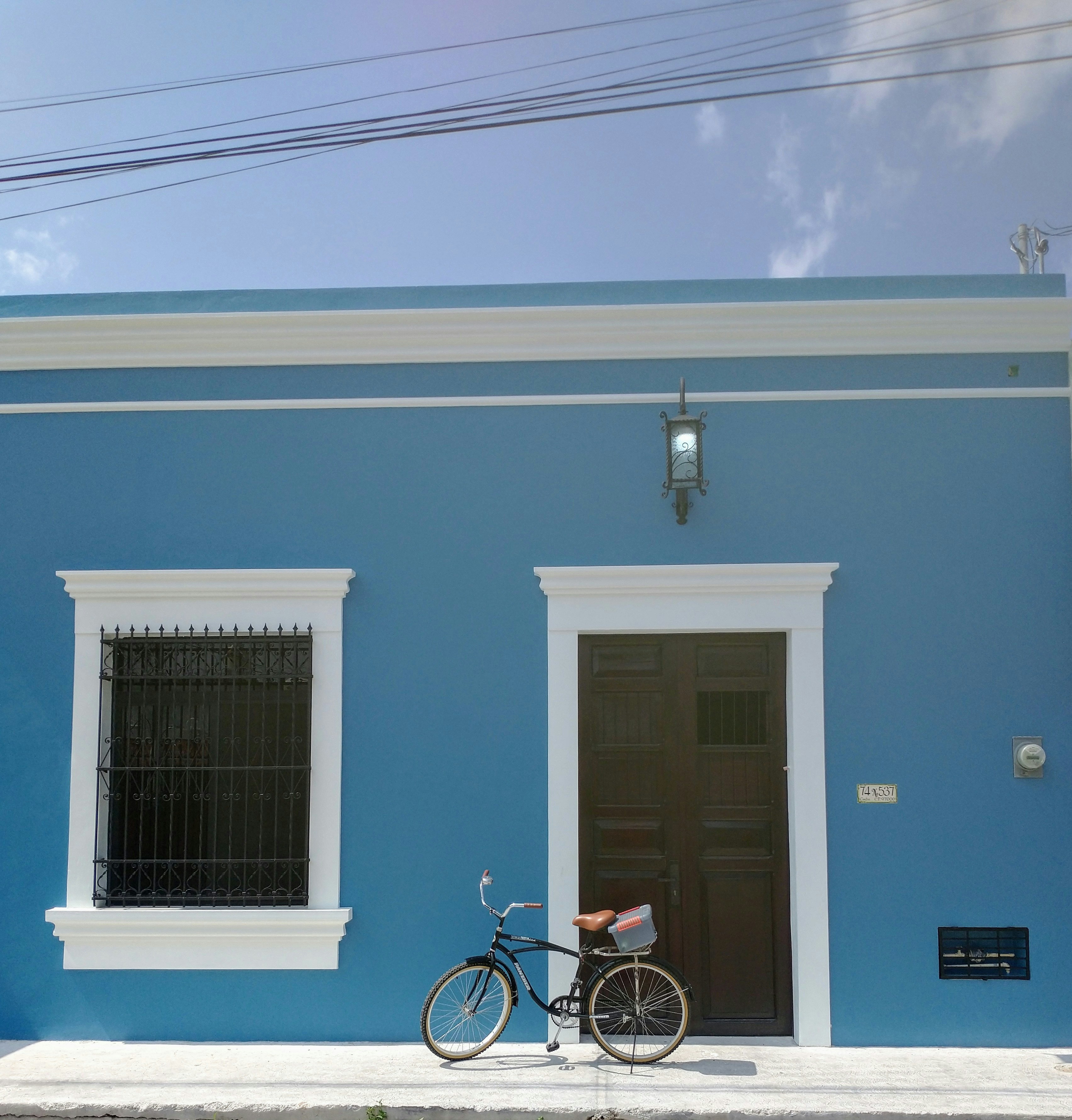 Bright blue house with white trim and a bicycle parked in front, showcasing a charming urban scene. The sunlight enhances the vivid colors and details of the architecture.