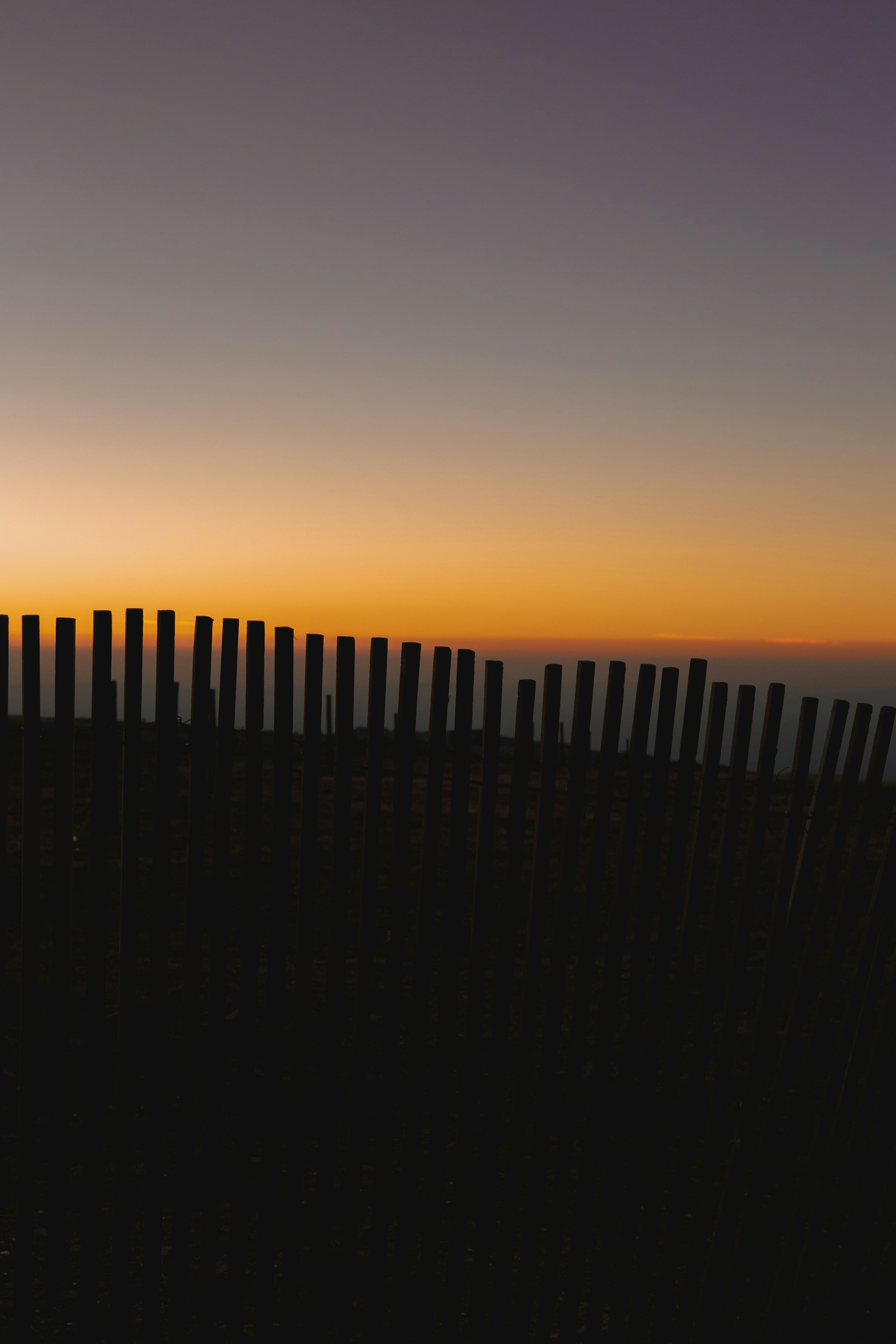 Ridge of Shadows at Dusk: Fence Posts Against a Gradient Horizon