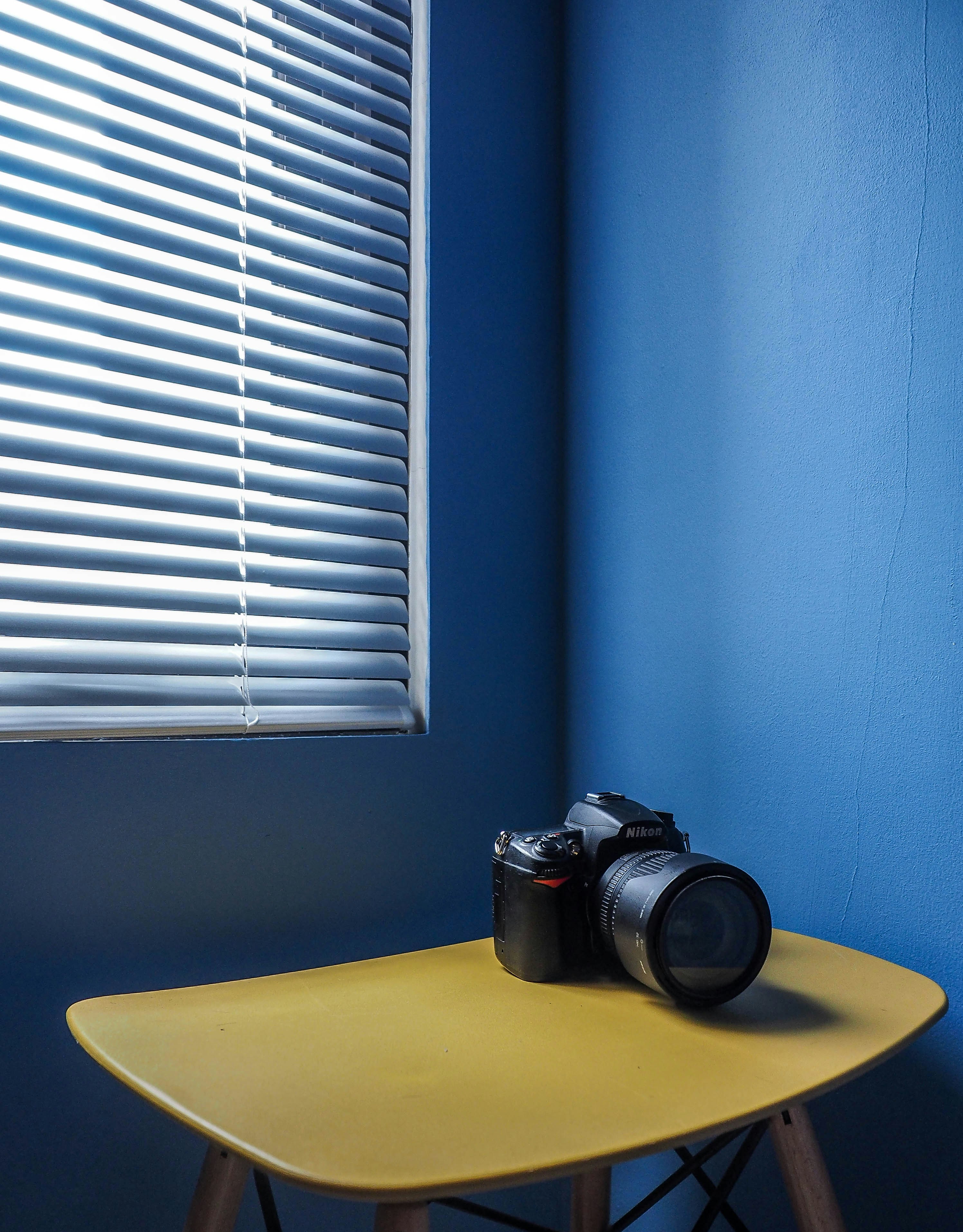 Yellow Table, Blue Wall, and a DSLR Resting in Quiet Corner