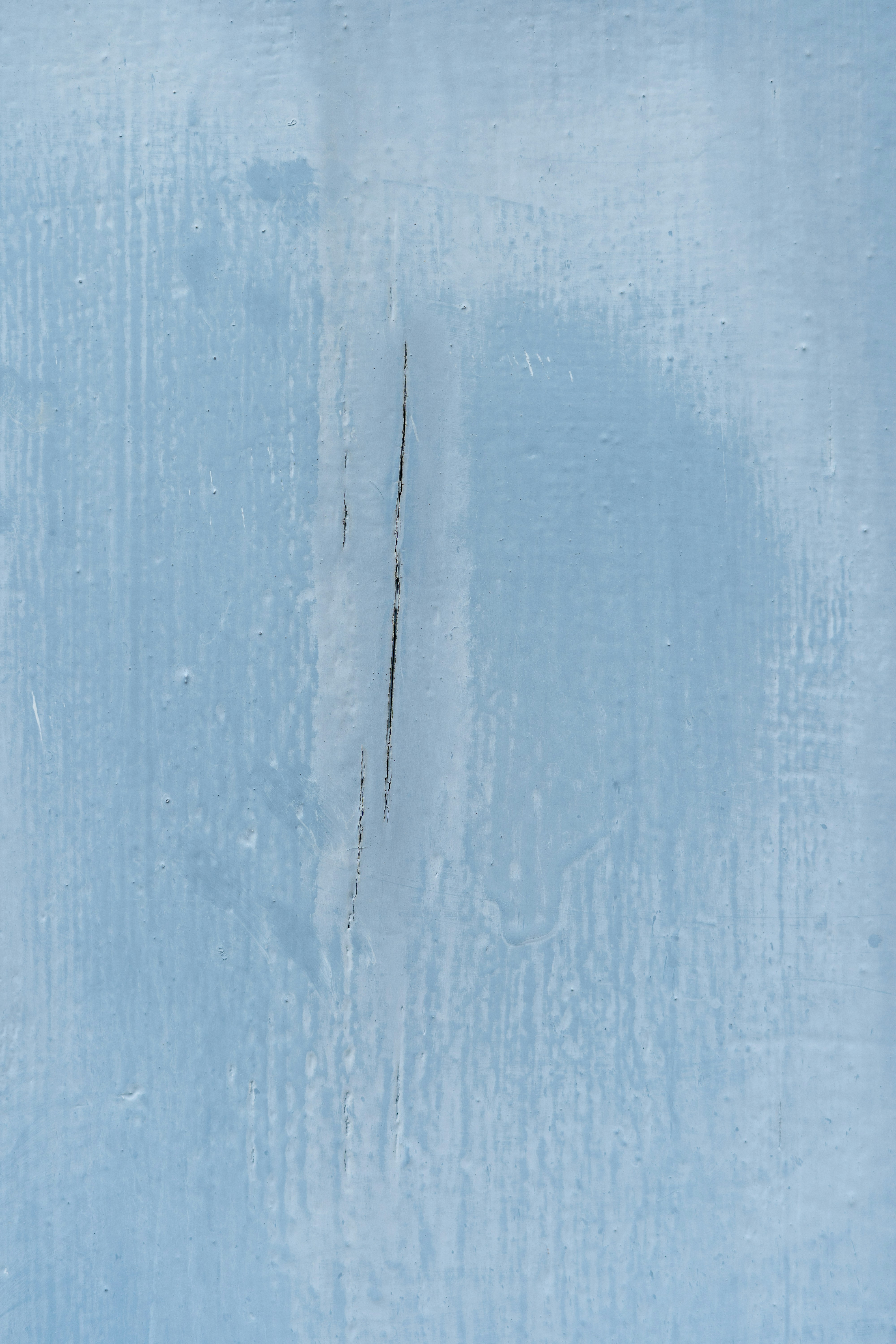 Close-up of a weathered blue surface with subtle textures and a prominent crack, suggesting age and character.