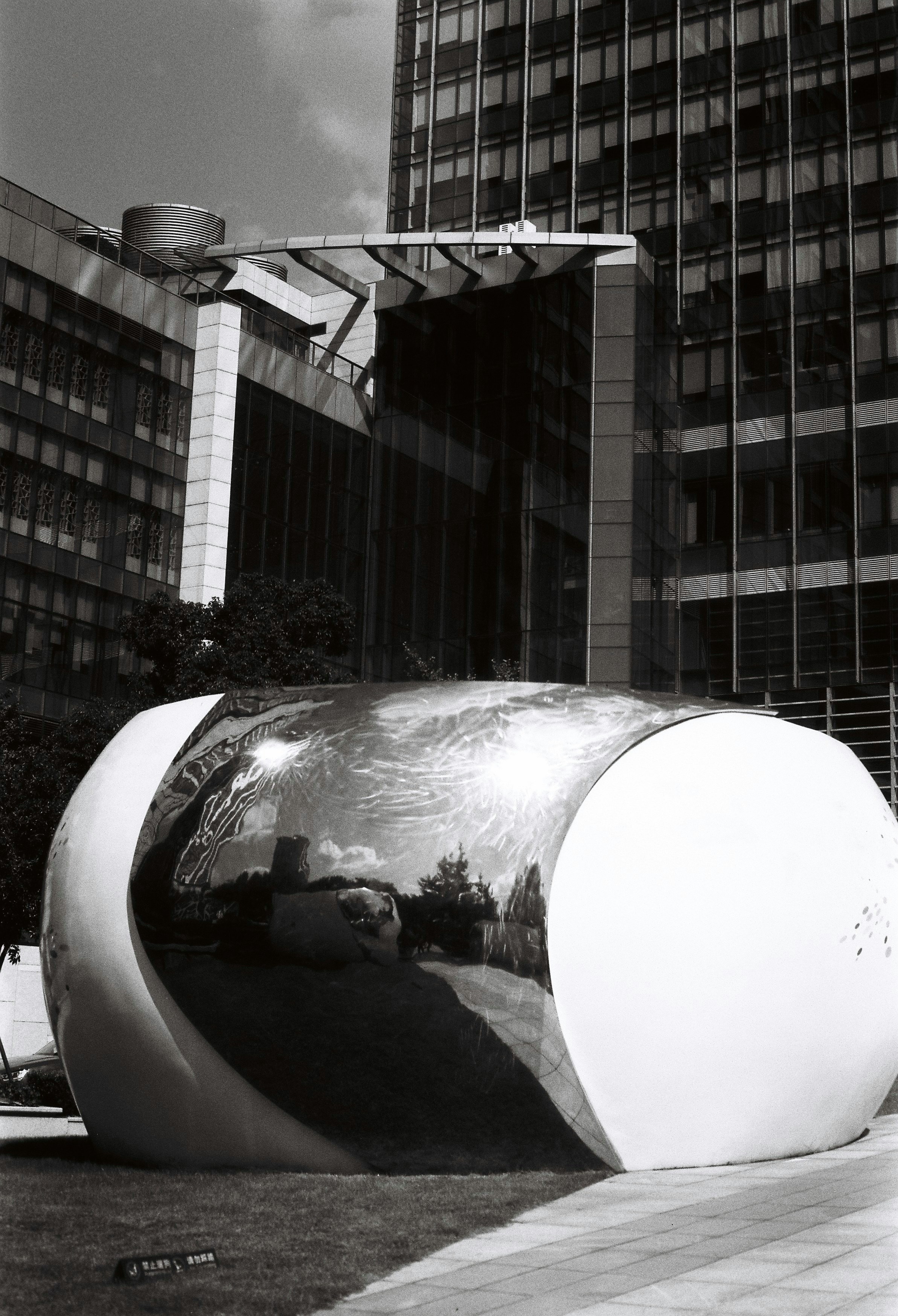 A large metal object sitting in front of a tall building photo – Free ...
