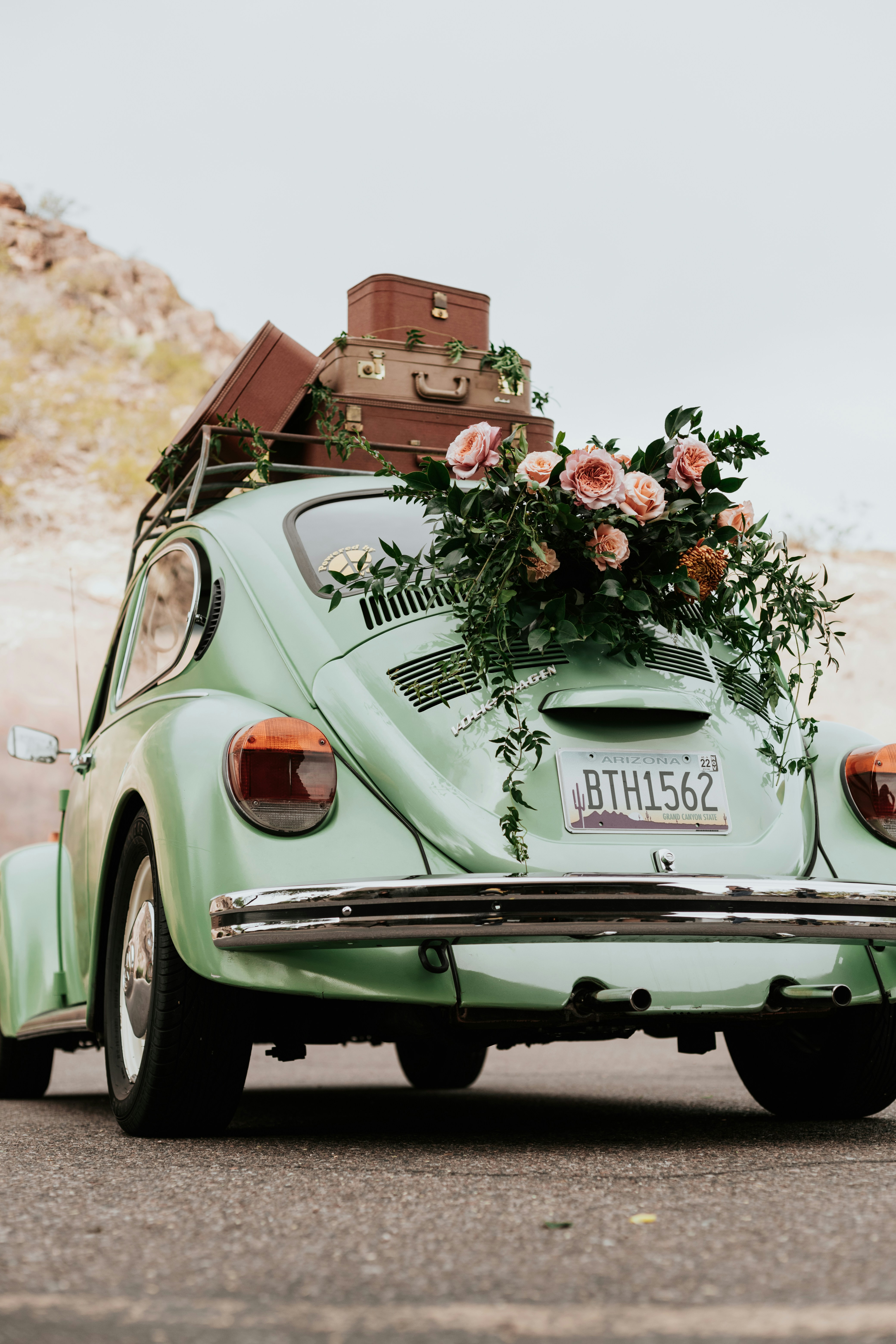 a green car with a bunch of flowers on top of it
