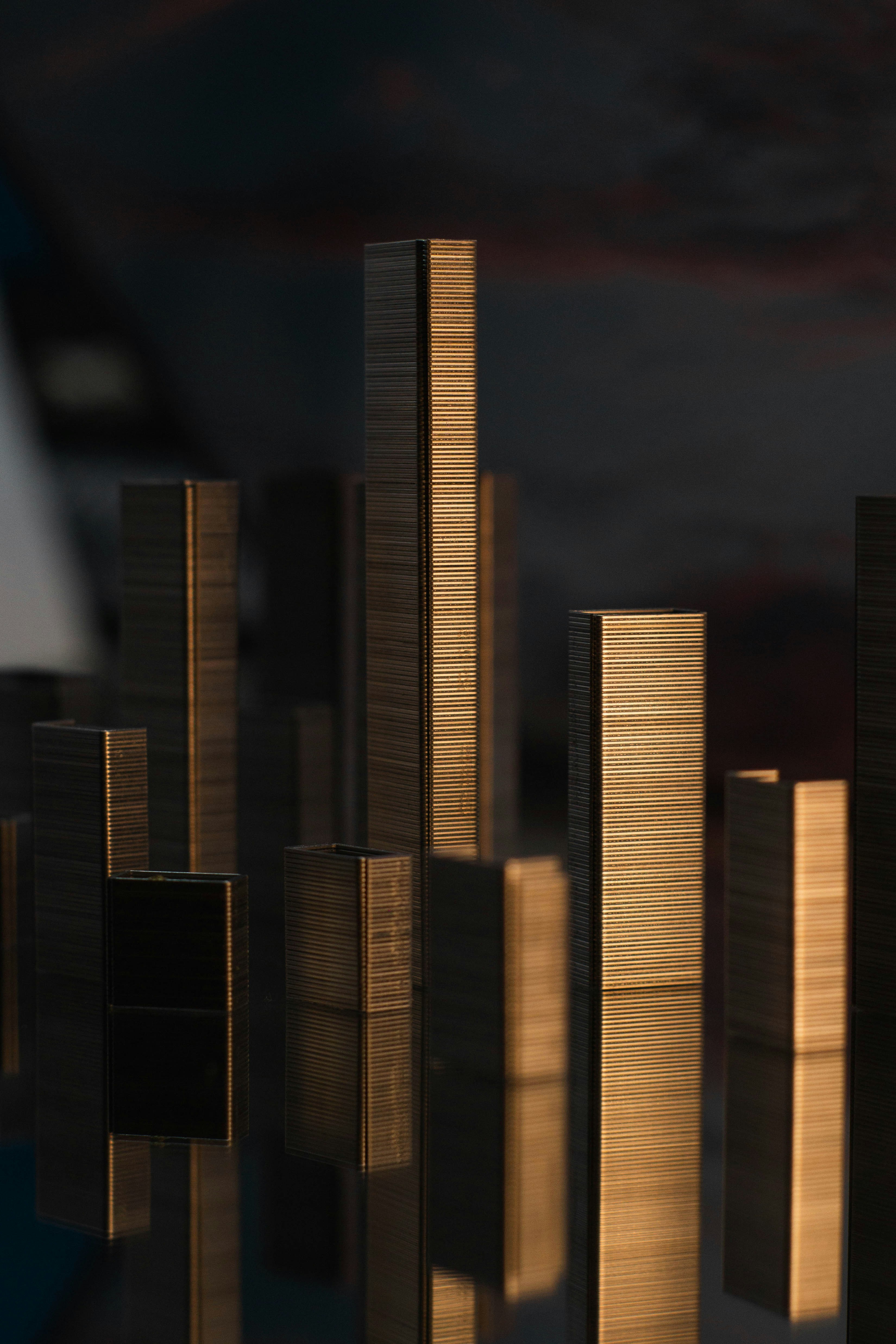 A collection of metallic rectangles resembling skyscrapers, reflecting light on a smooth surface, creating an abstract urban scene.