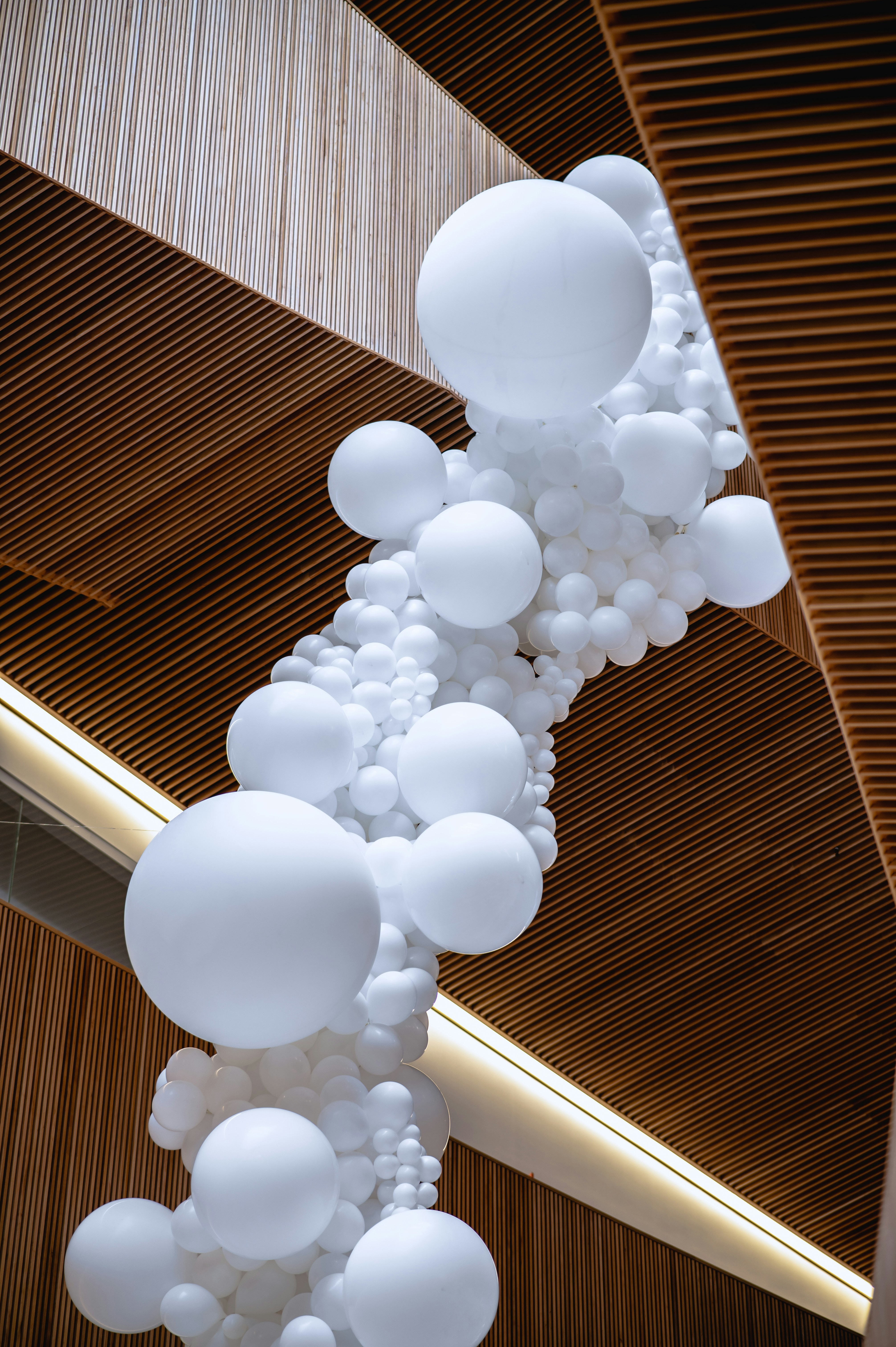 Ascending Cloud: Balloon Cascade Through Wood-Panelled Atrium