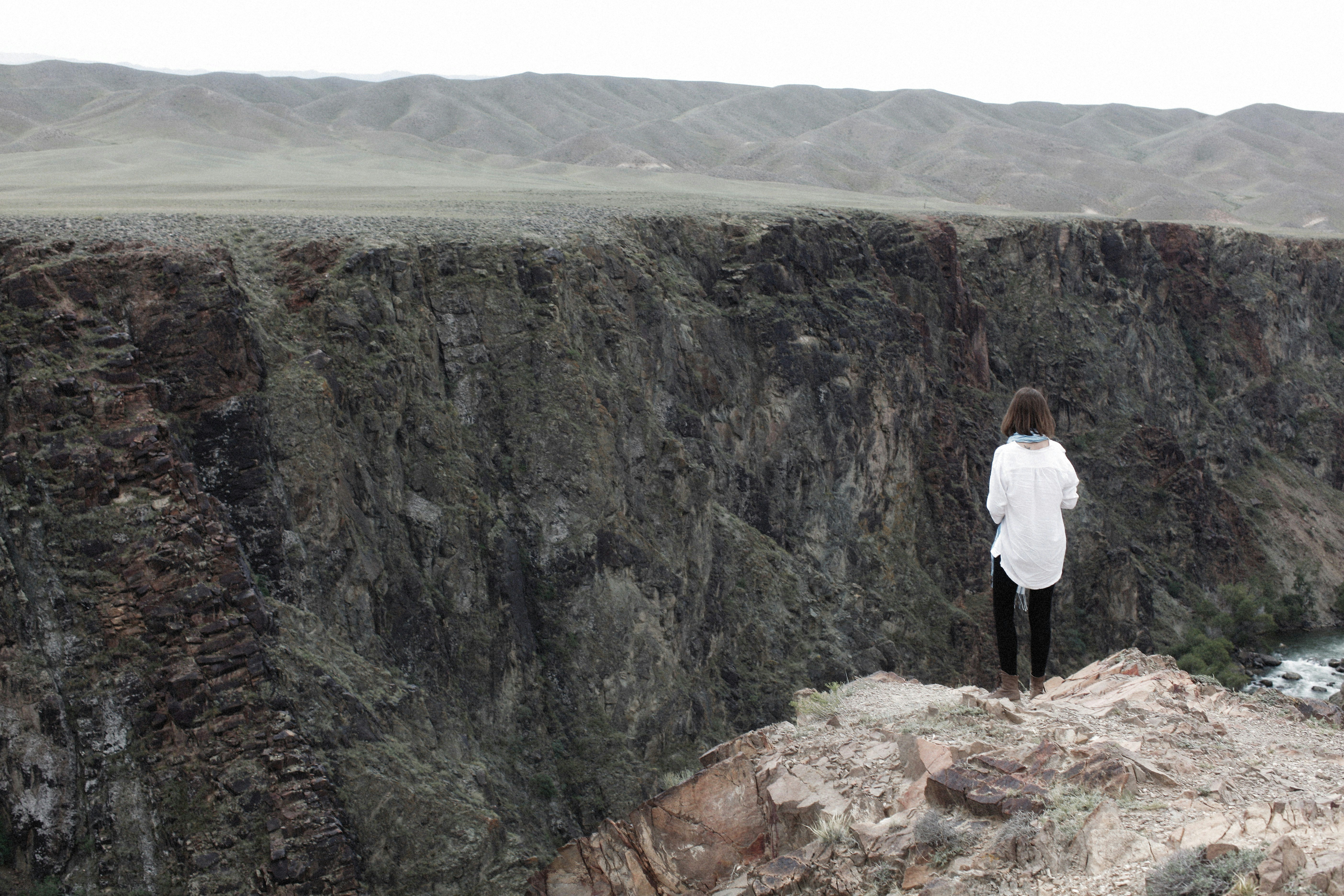A person standing on top of a cliff photo – Free Grey Image on Unsplash
