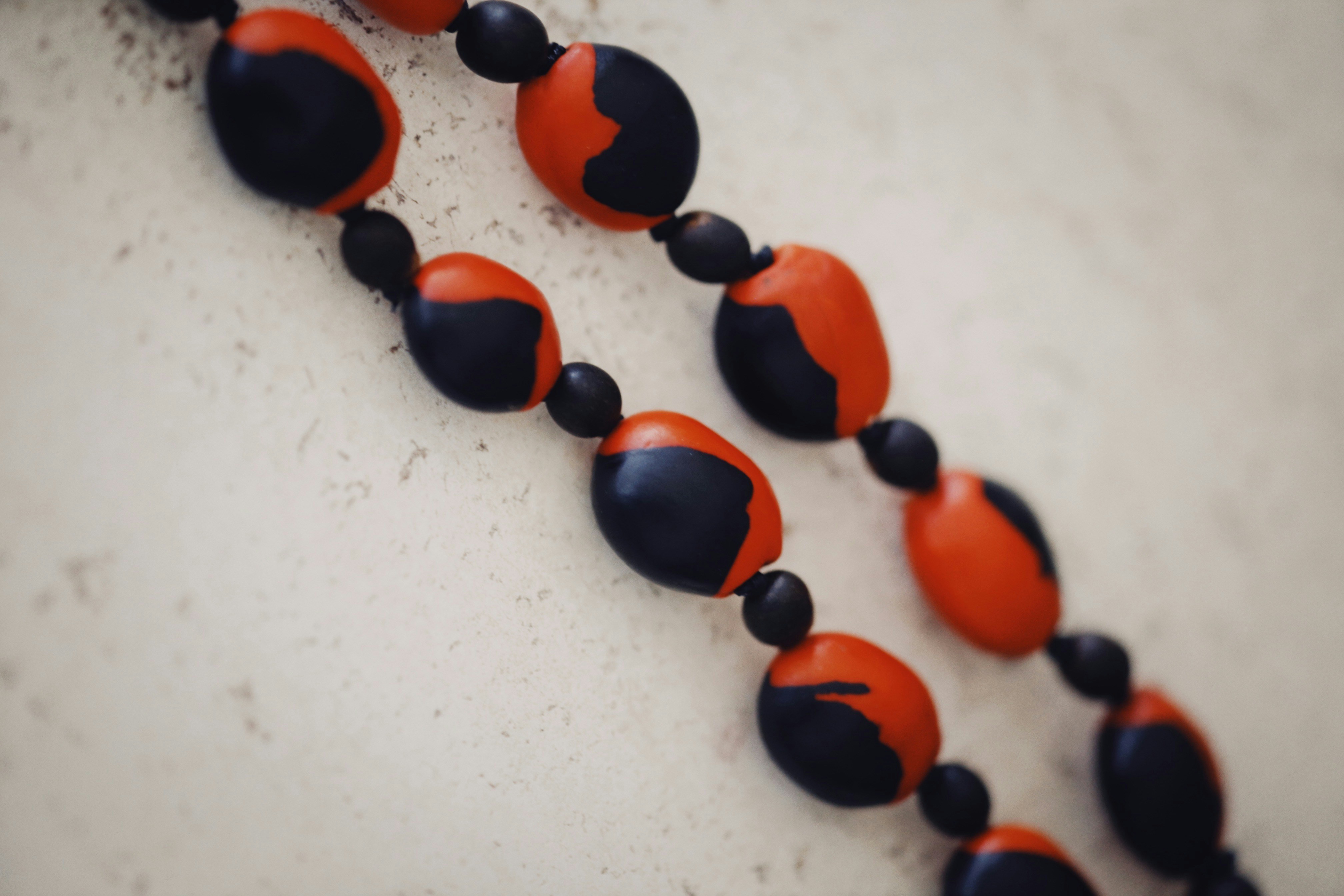 Close-up of a handcrafted necklace featuring black and red beads arranged in a rhythmic pattern.