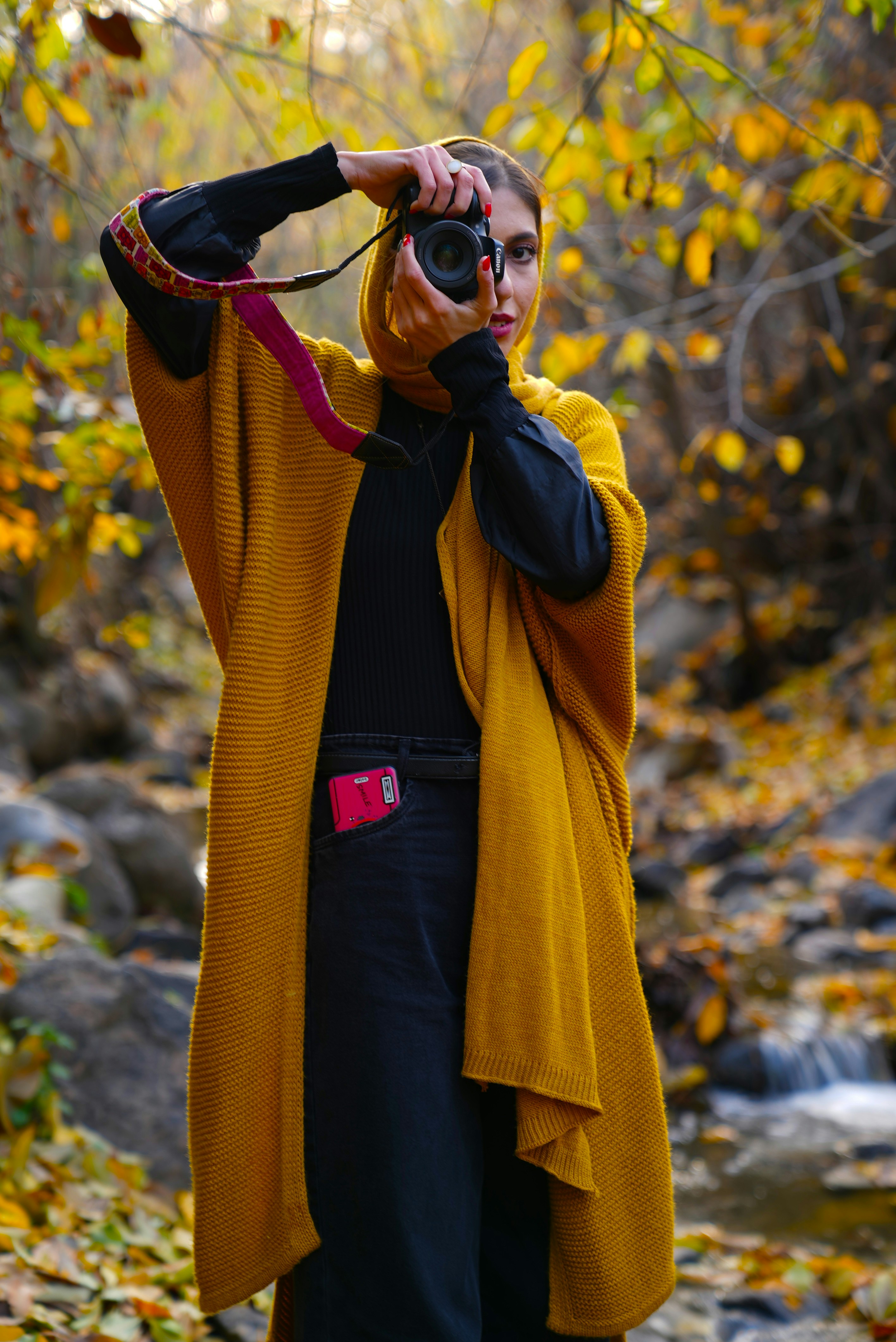 Beautiful girl in the autumn forest with a camera in hand 