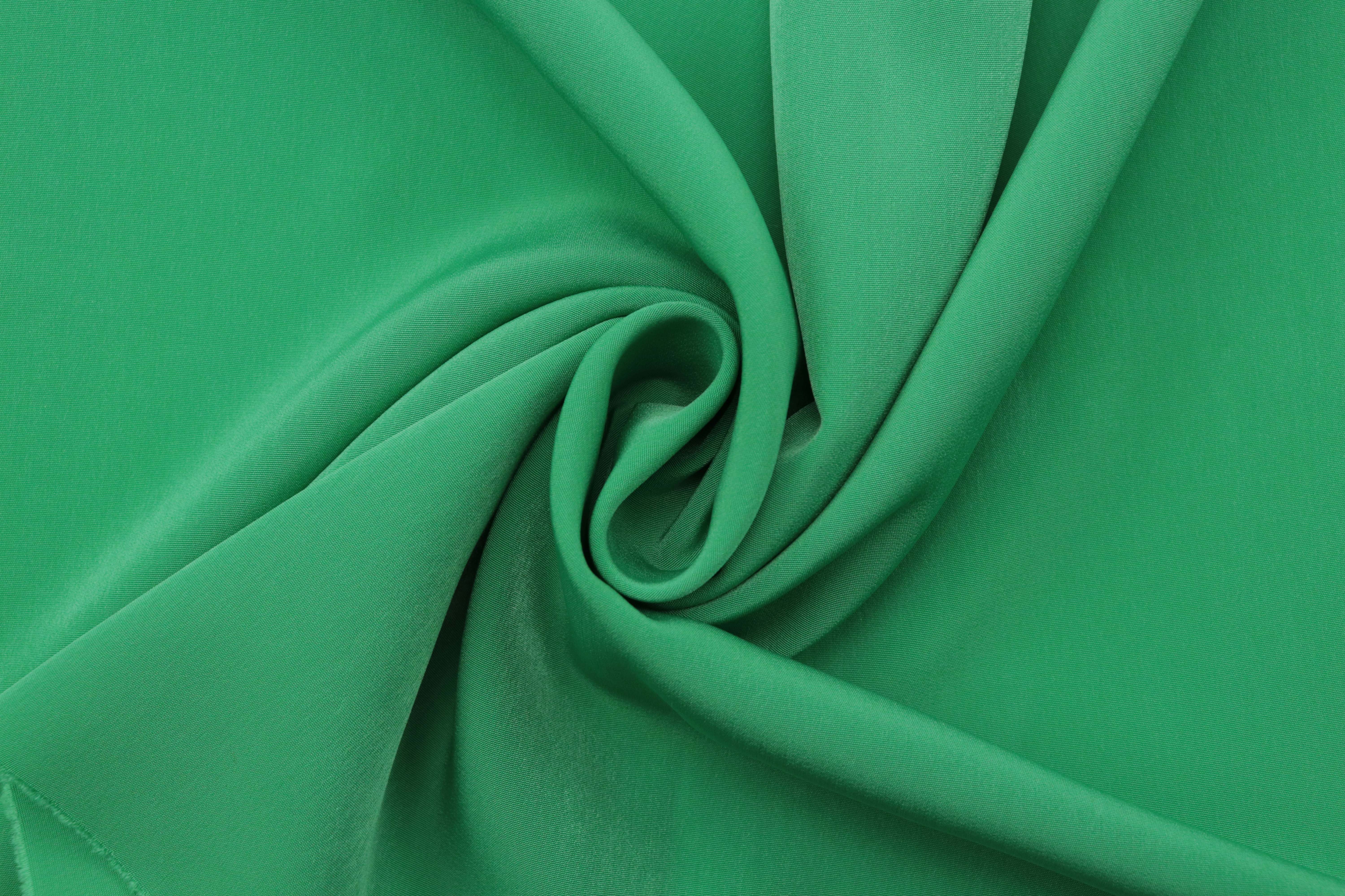 Swirling green fabric creating a dynamic texture and depth, showcasing the interplay of light and shadow.
