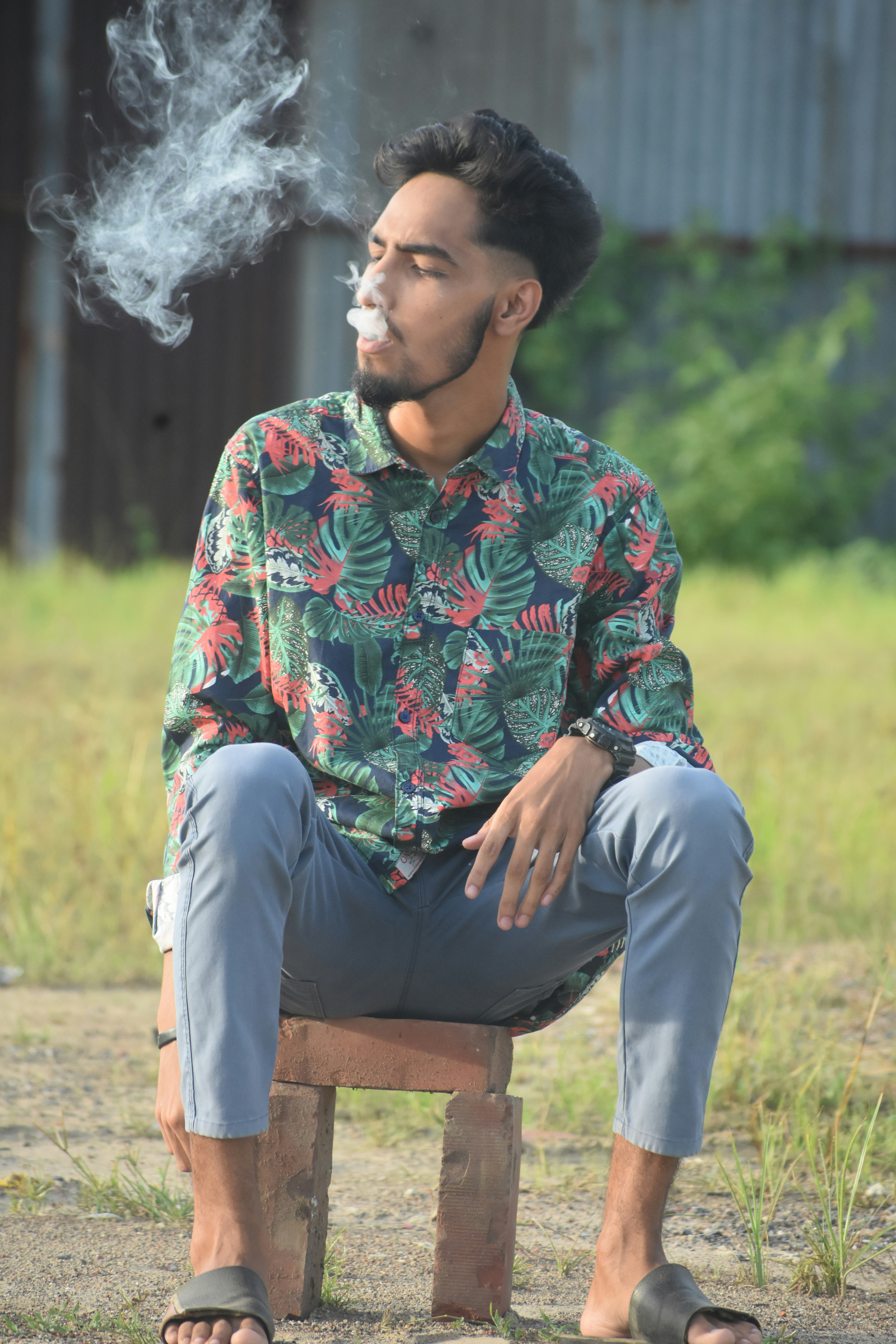 A man sitting on a stool smoking a cigarette photo – Free Human Image ...