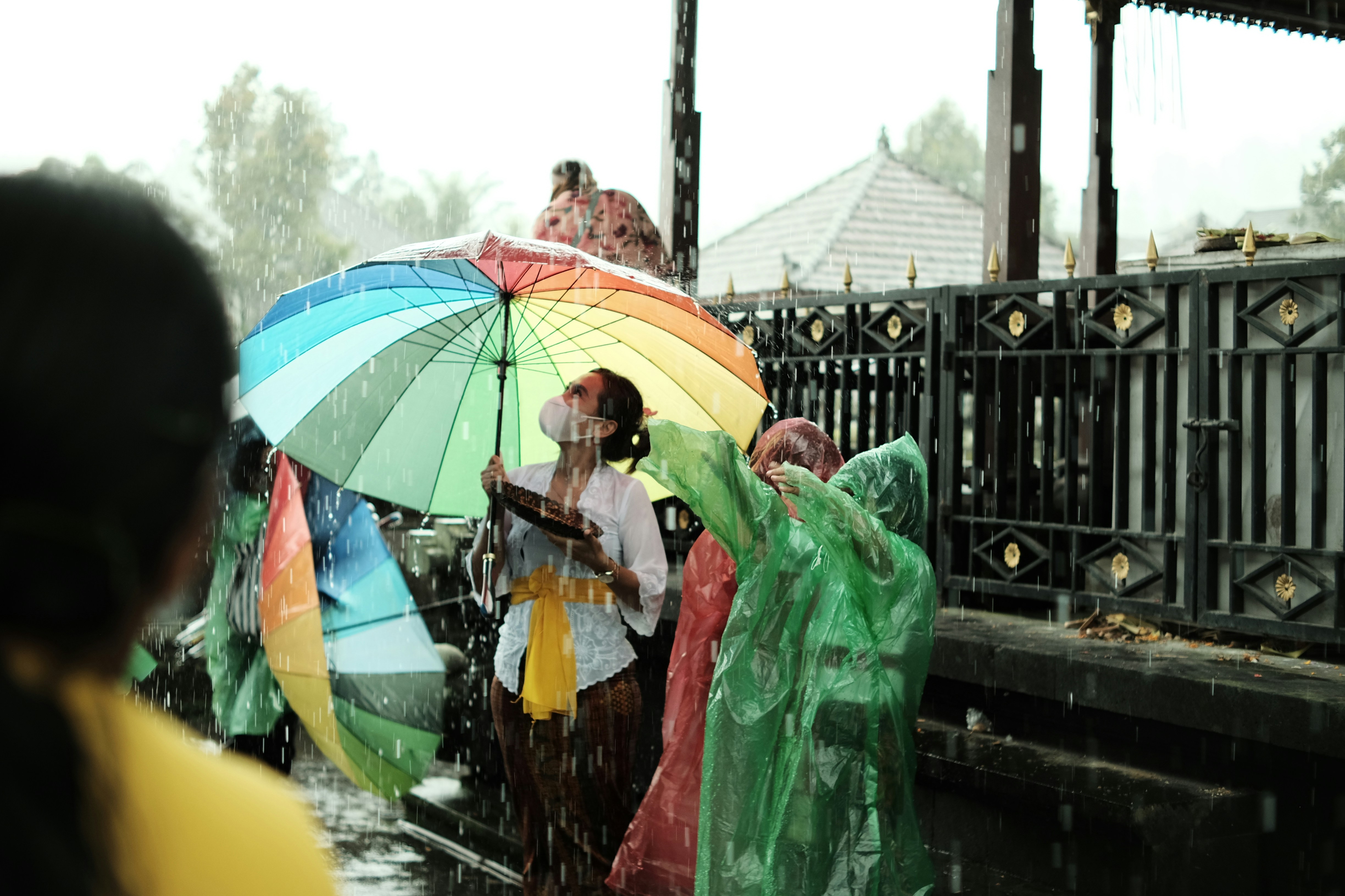 Chromatic Shelter: Rainbow Umbrella Moment on a Rain-Washed Platform