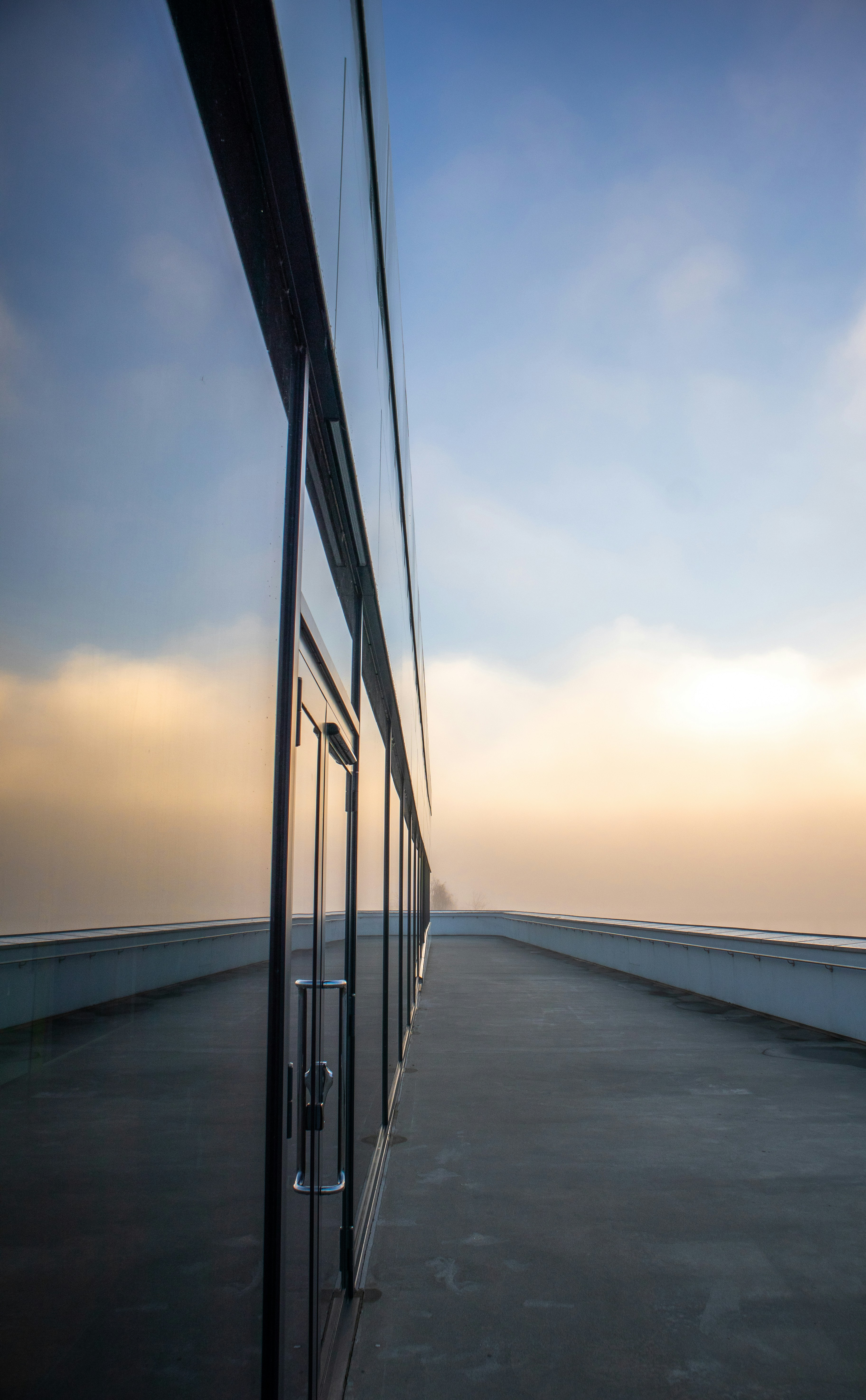 Vanishing Corridor: Rooftop Glass Walls Toward the Sunset