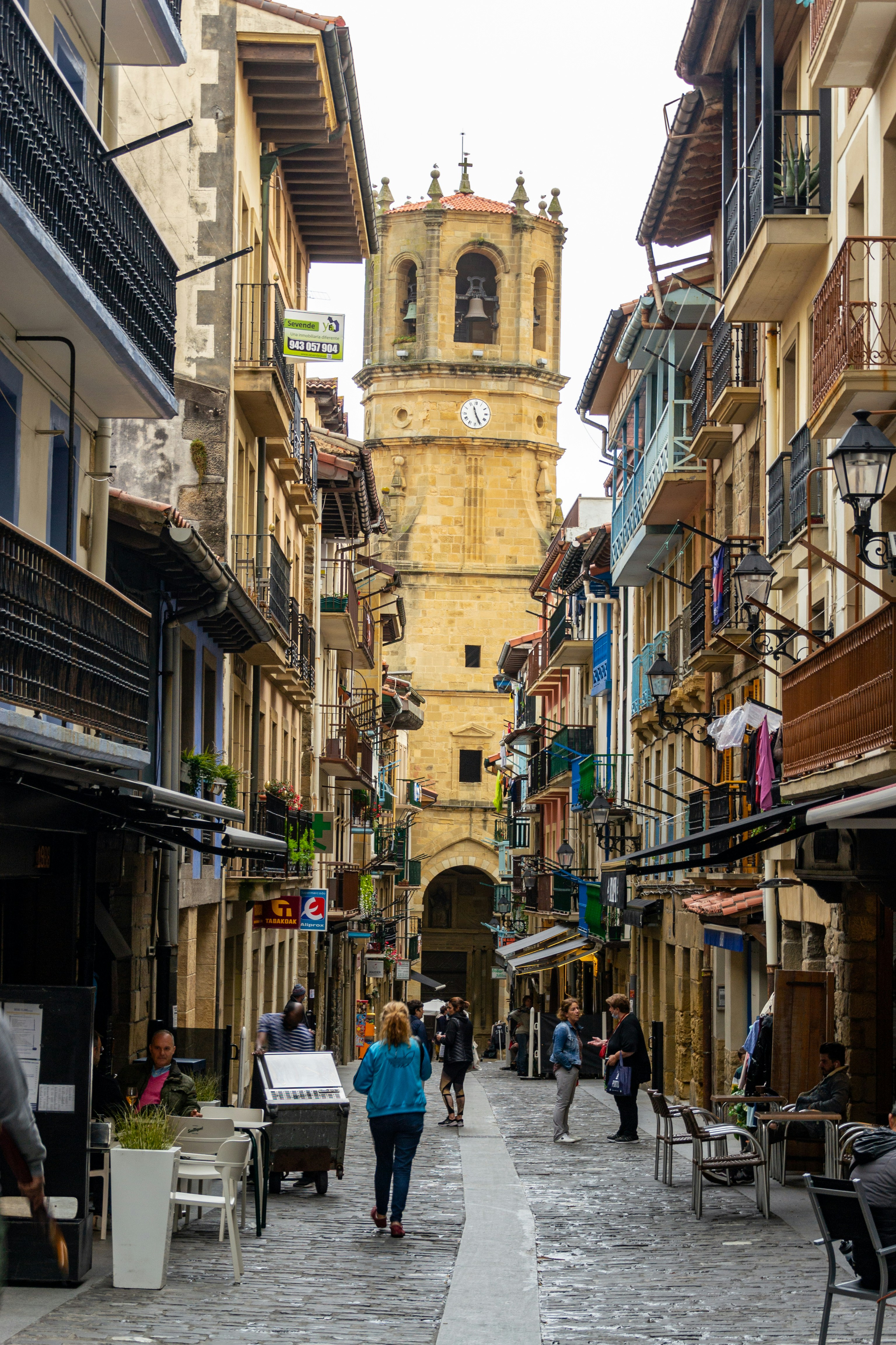 Clock Tower Corridor: A Sunlit Basque Street Framed by Balconies