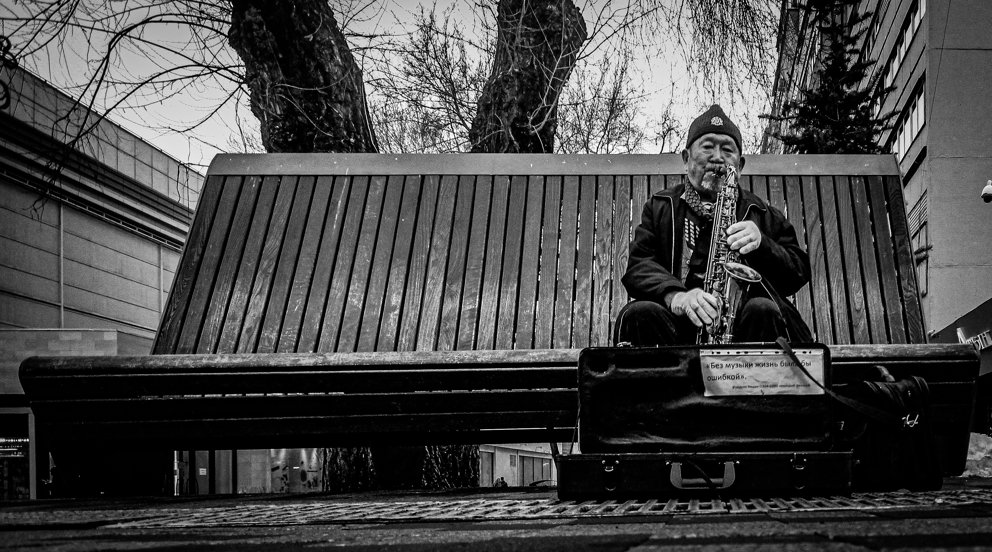 A man sitting on a bench playing a saxophone photo – Free Music Image ...