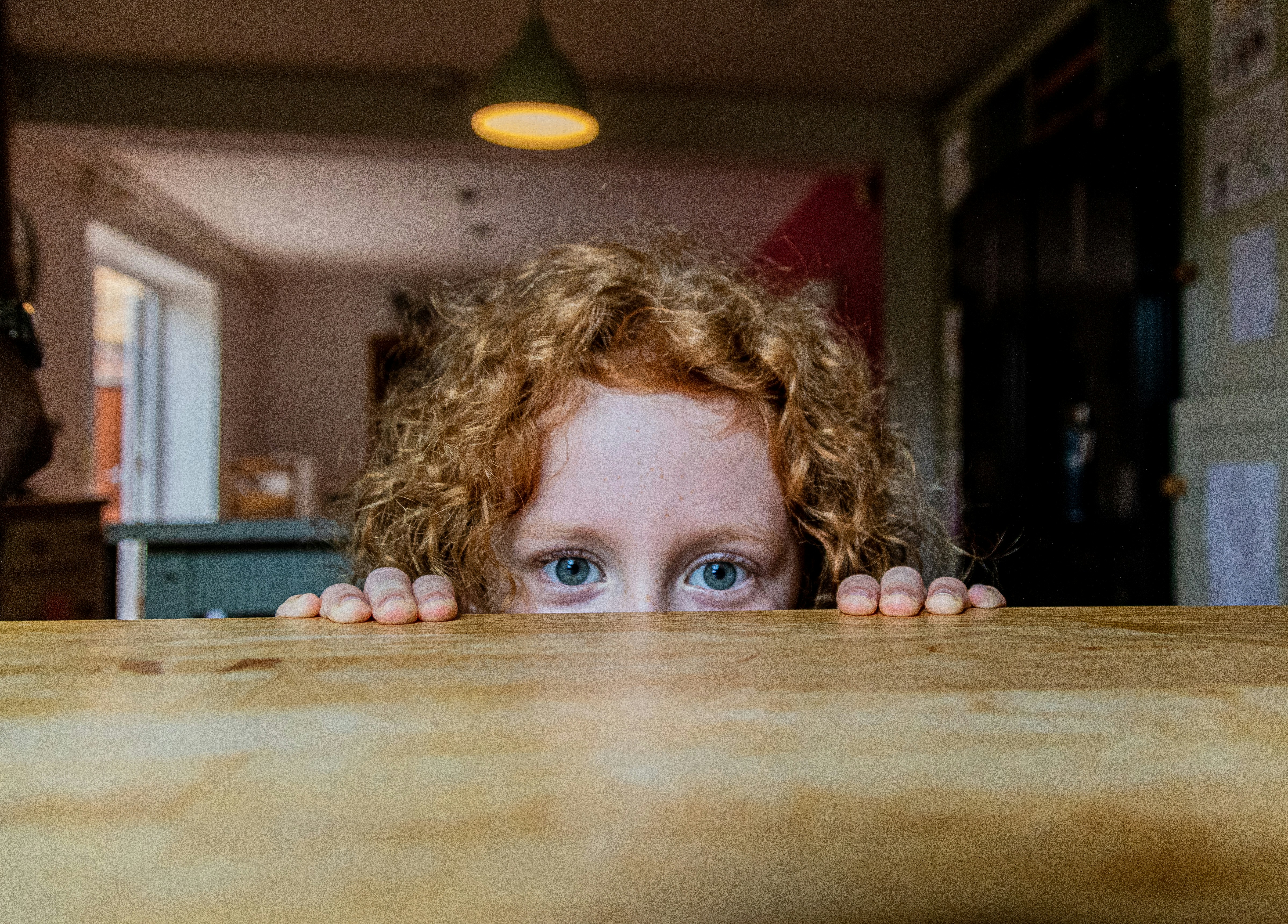 A young girl peeking over a wooden table photo – Free Ginger Image on ...
