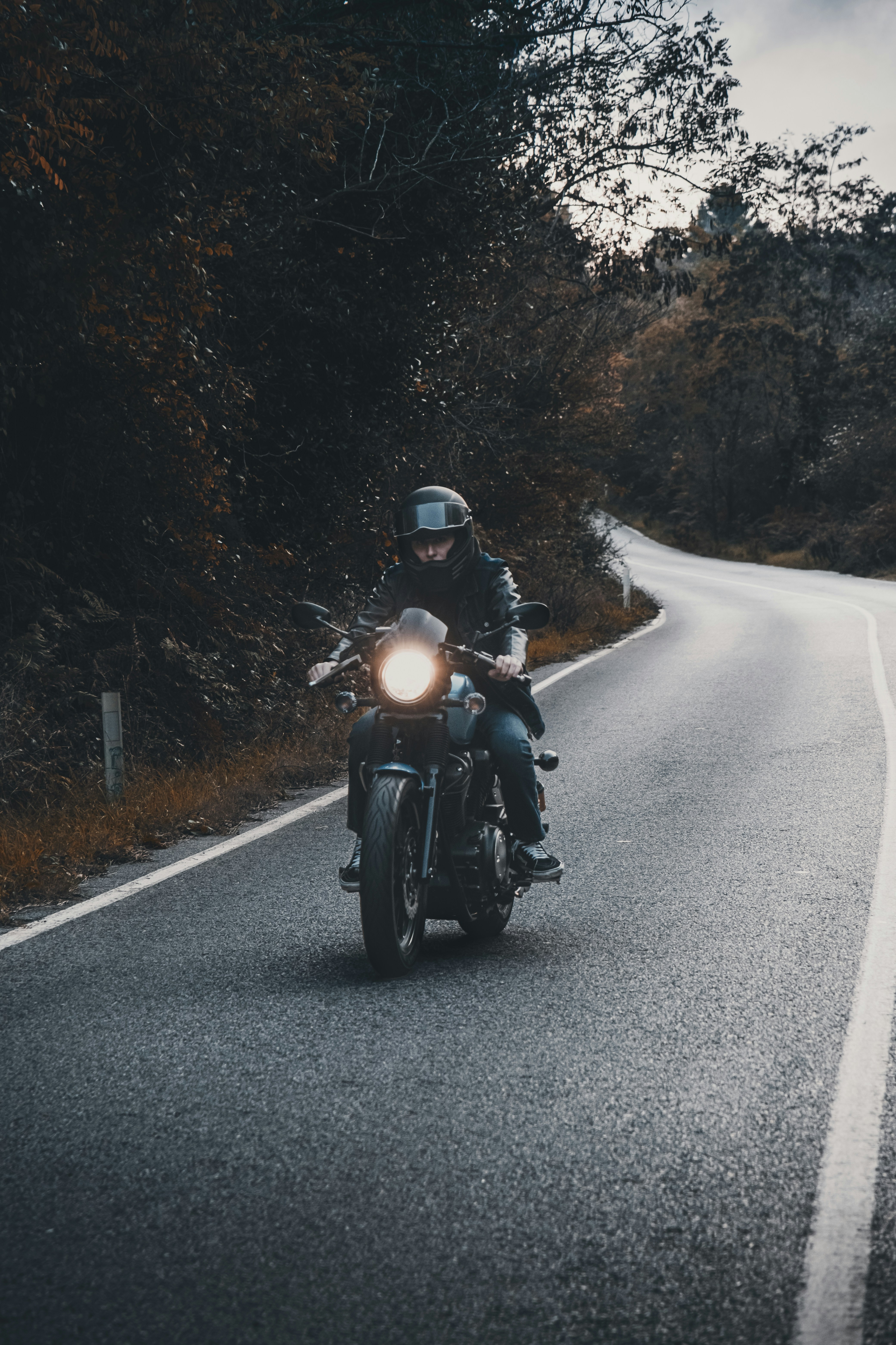A man riding a motorcycle down a curvy road photo – Free Person Image ...