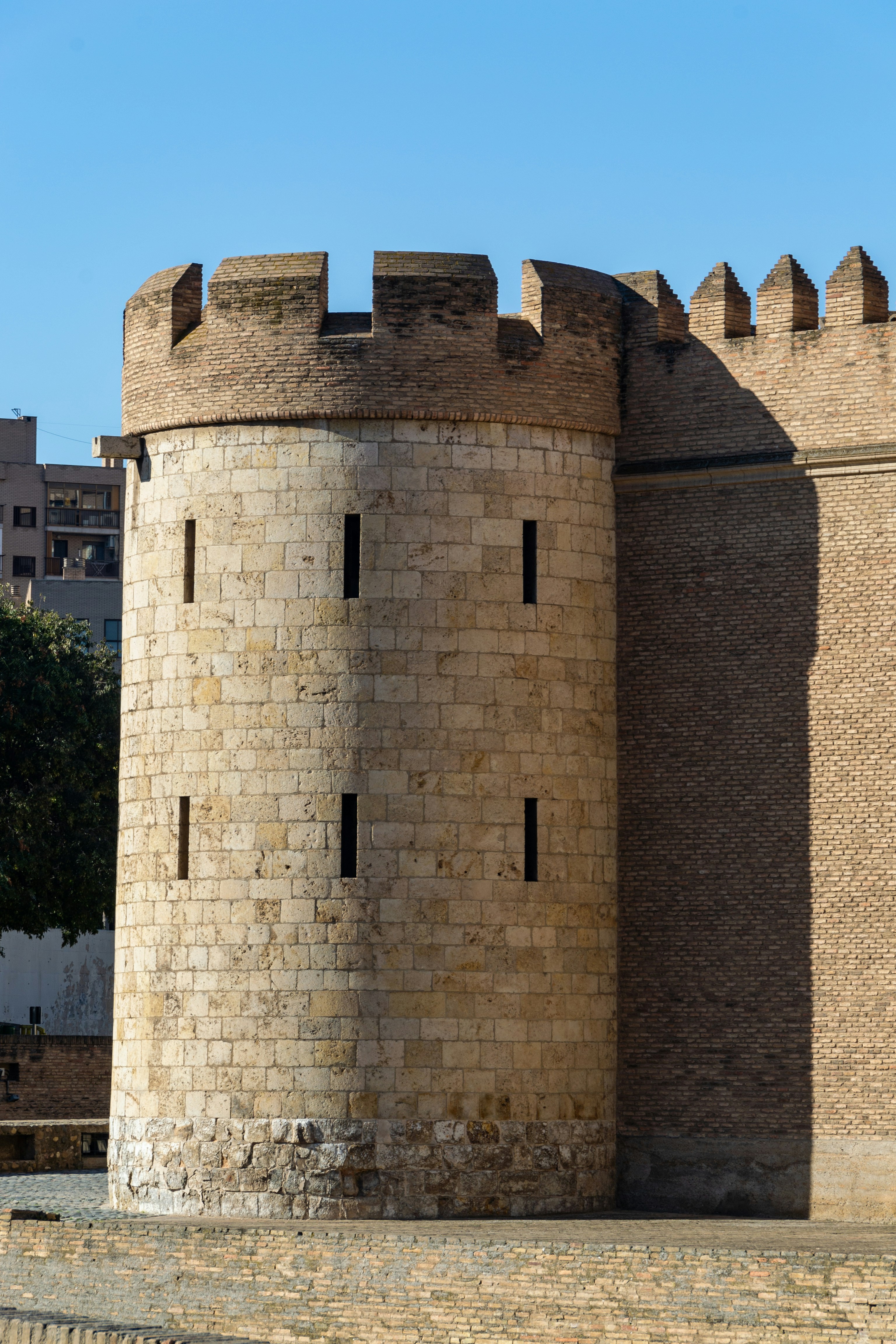 A tall brick tower sitting next to a brick wall photo – Free Zaragoza ...