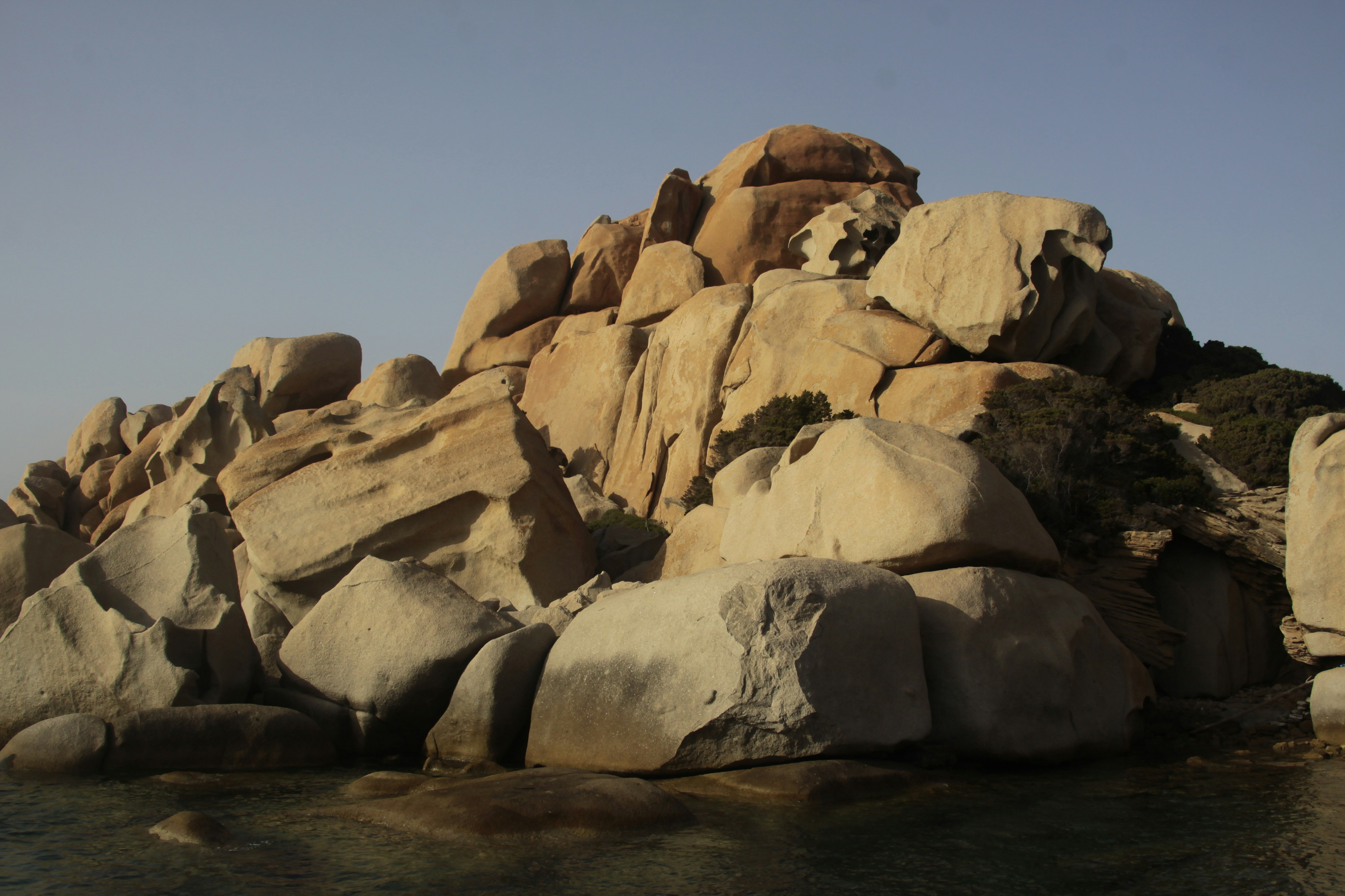 Granite boulders shaped by time and elements, showcasing intricate textures and hues along a serene coastline.