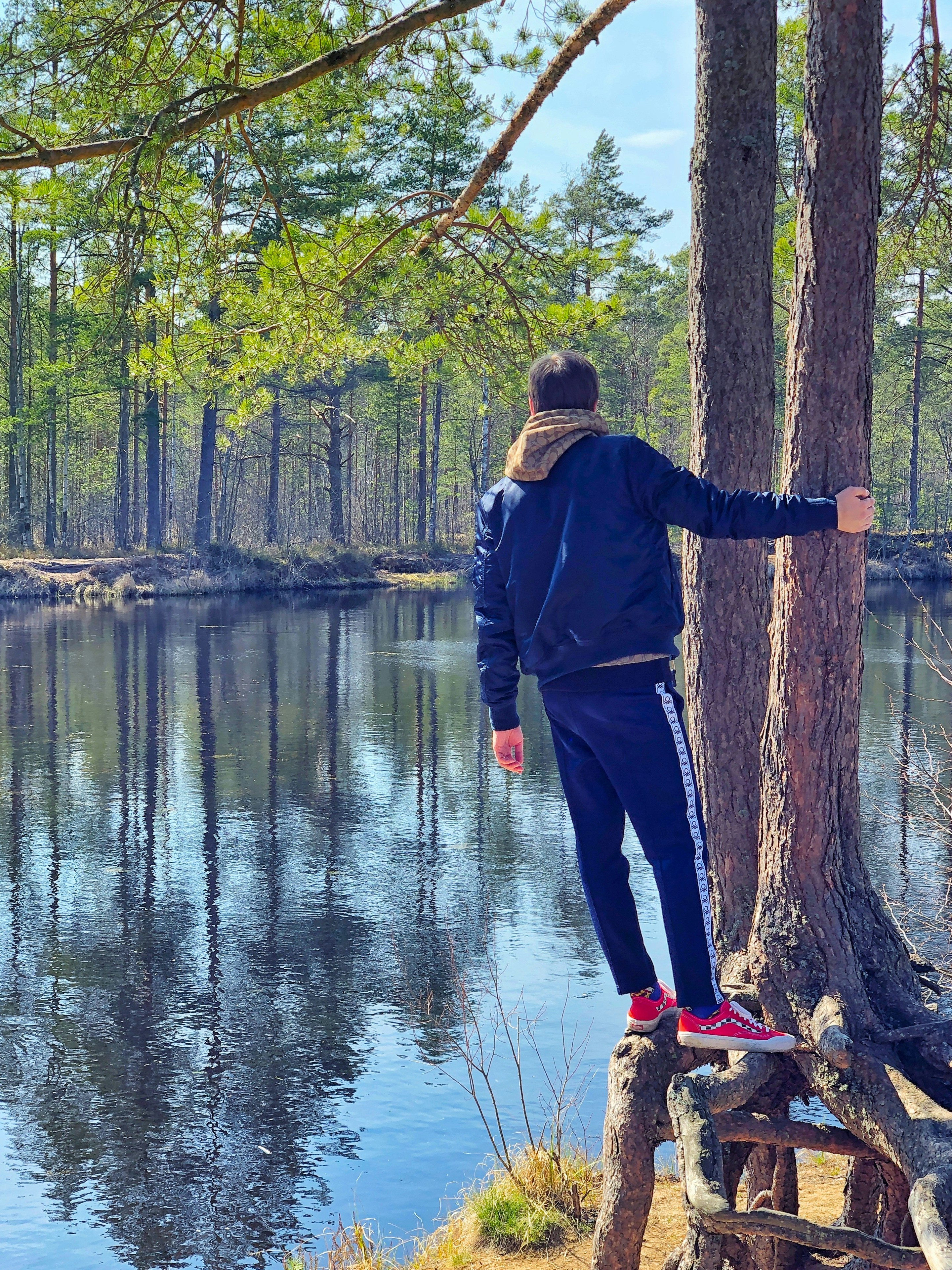 Un homme debout sur un tronc d’arbre au bord d’un lac photo – Photo La ...