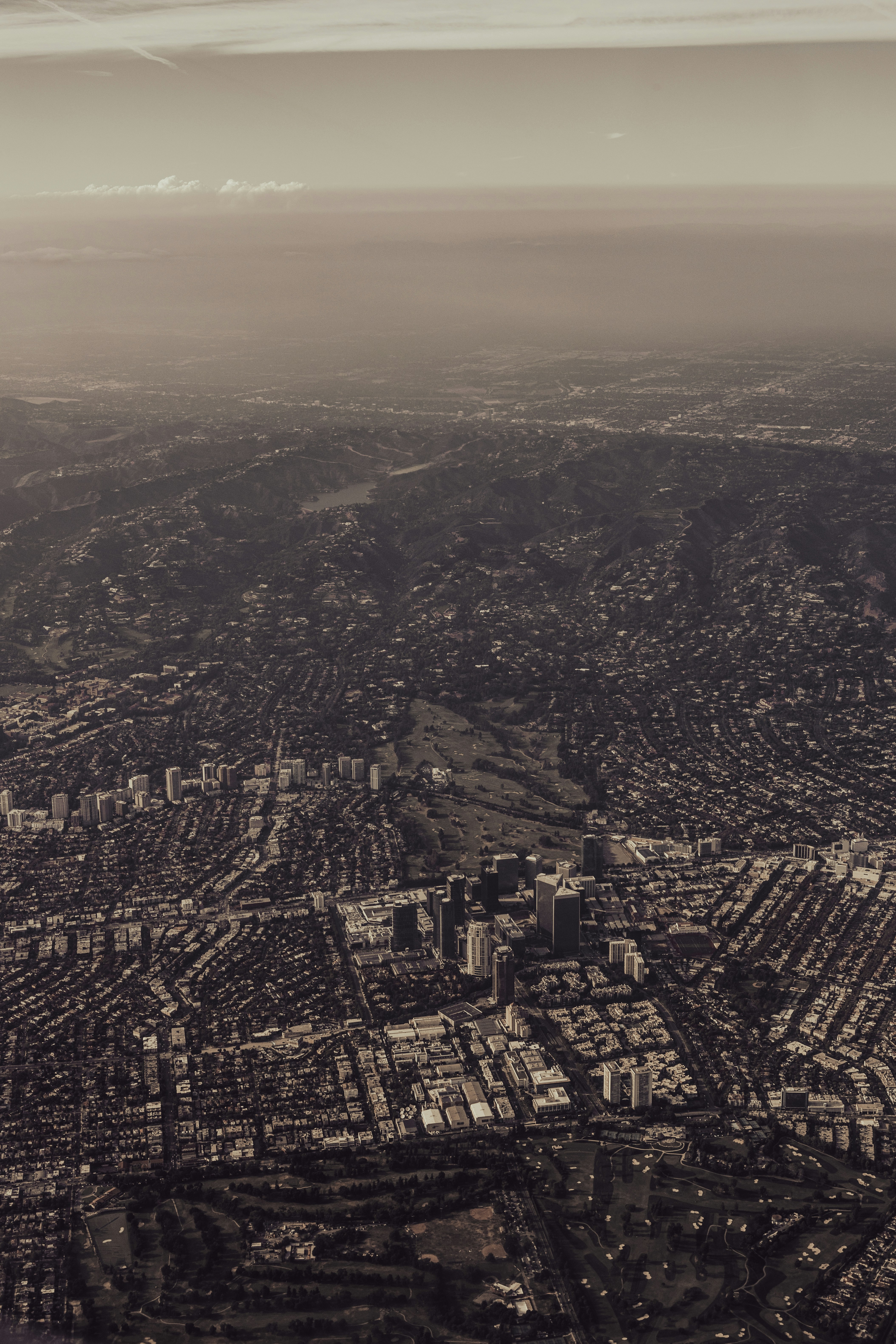 Aerial view showcasing a sprawling urban landscape with a mix of residential and commercial buildings, interspersed with green spaces. The cityscape captures the intricate layout of streets and structures.