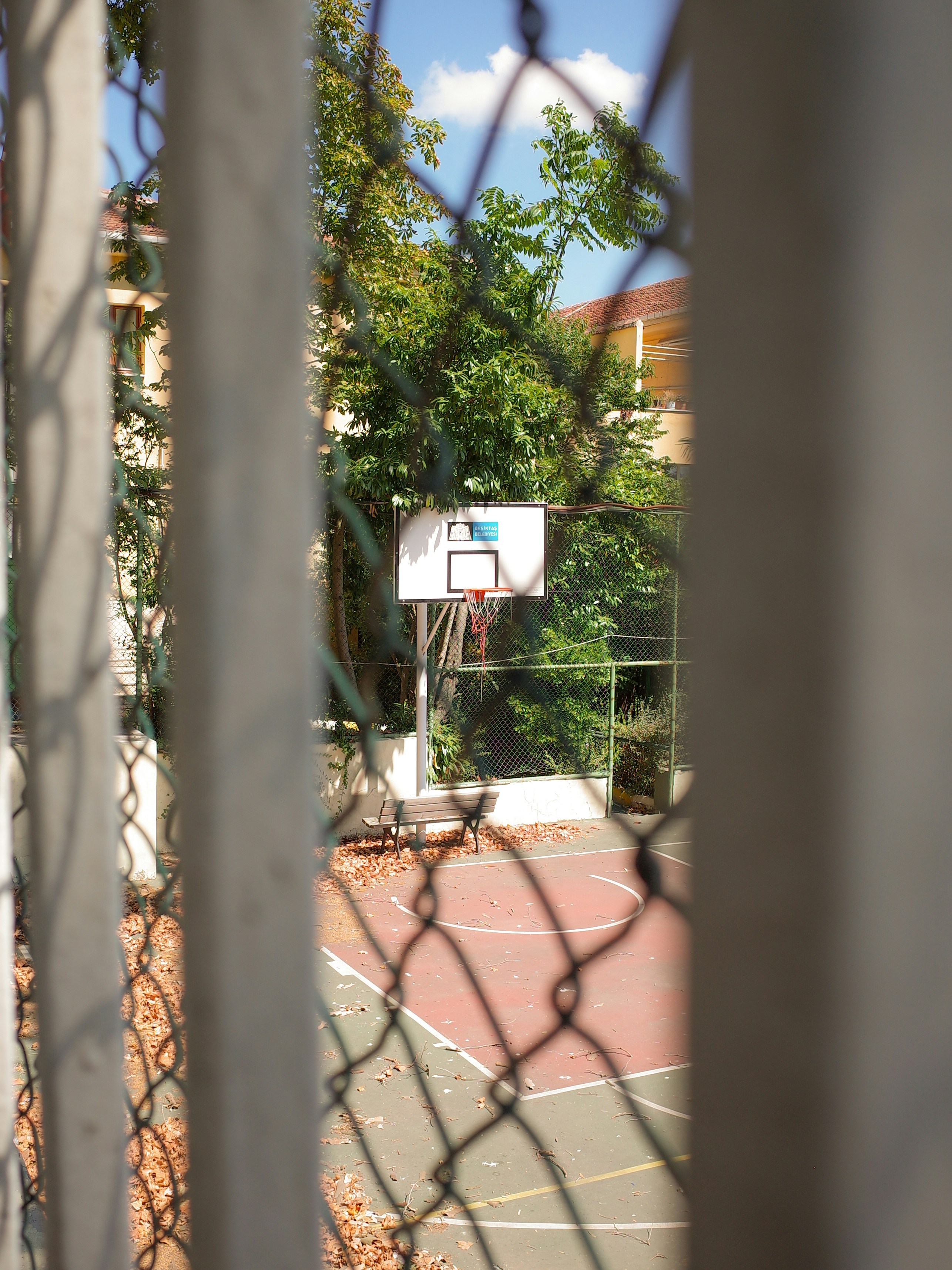 a view of a basketball court through a chain link fence