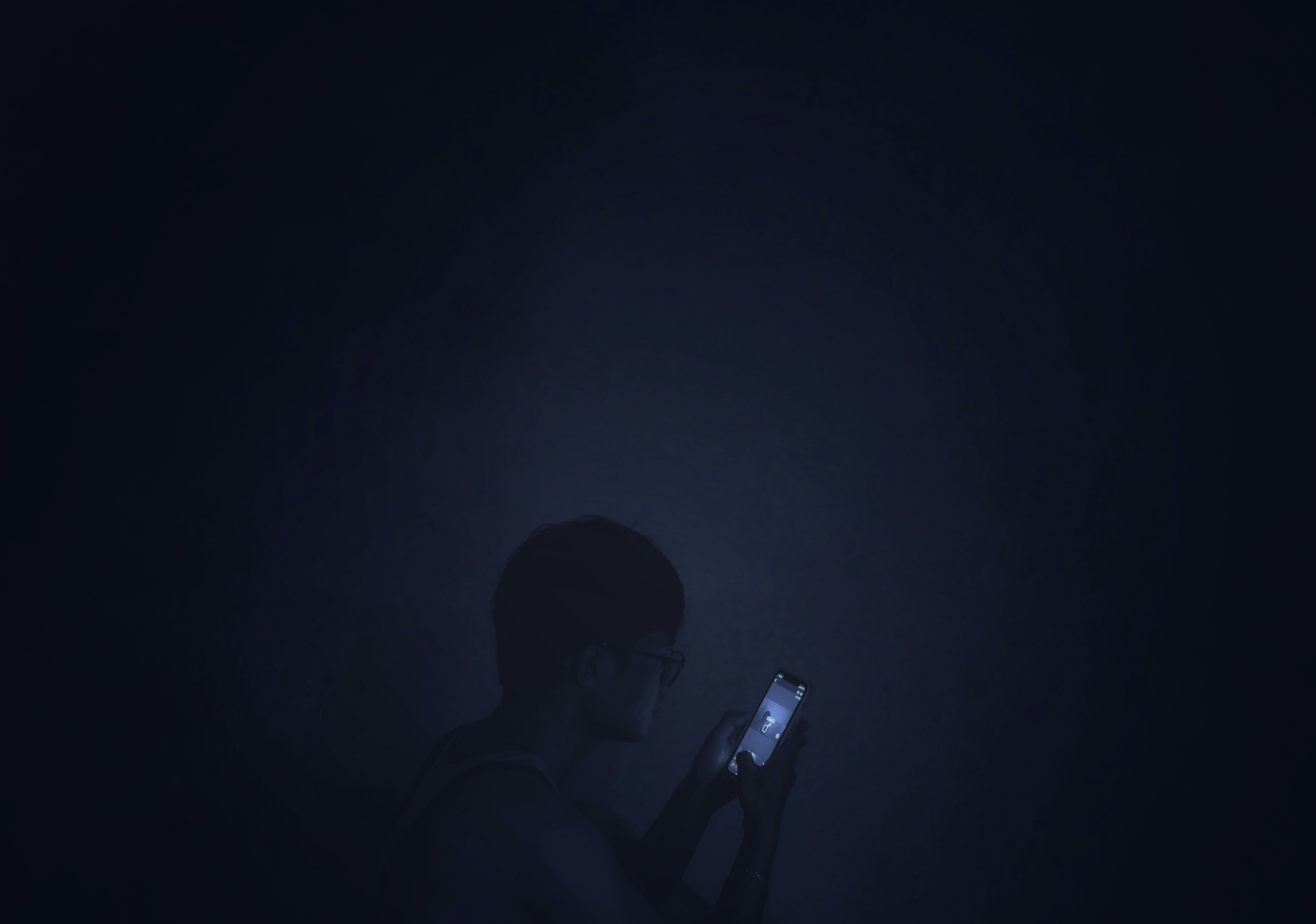 A man holding a cell phone in the dark photo – Free Portrait Image on ...