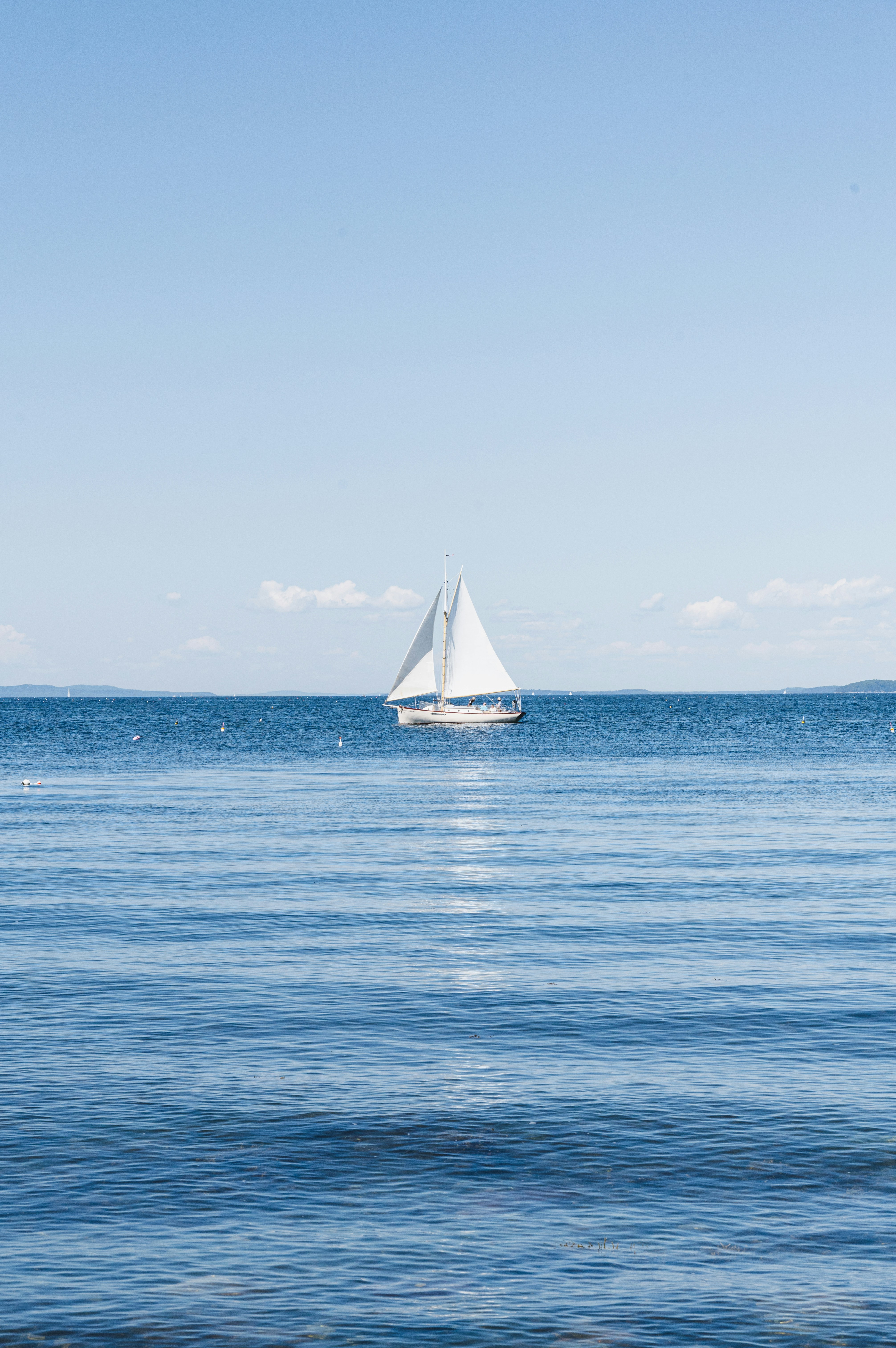 Sailboat gliding smoothly across a calm blue sea under a clear sky. The scene captures the essence of peaceful maritime exploration.