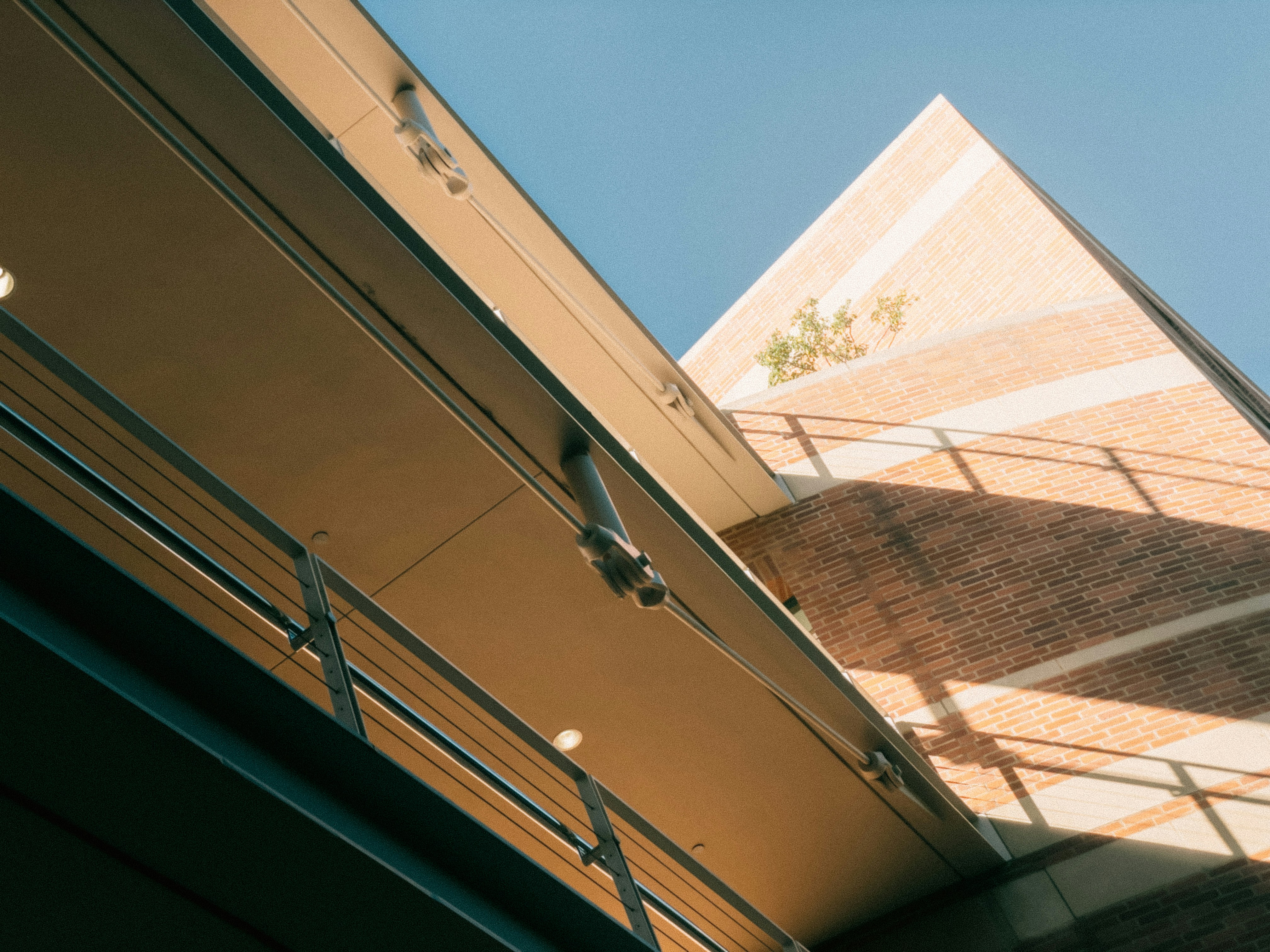 Architectural lines and shadows play across a building facade under a clear blue sky.