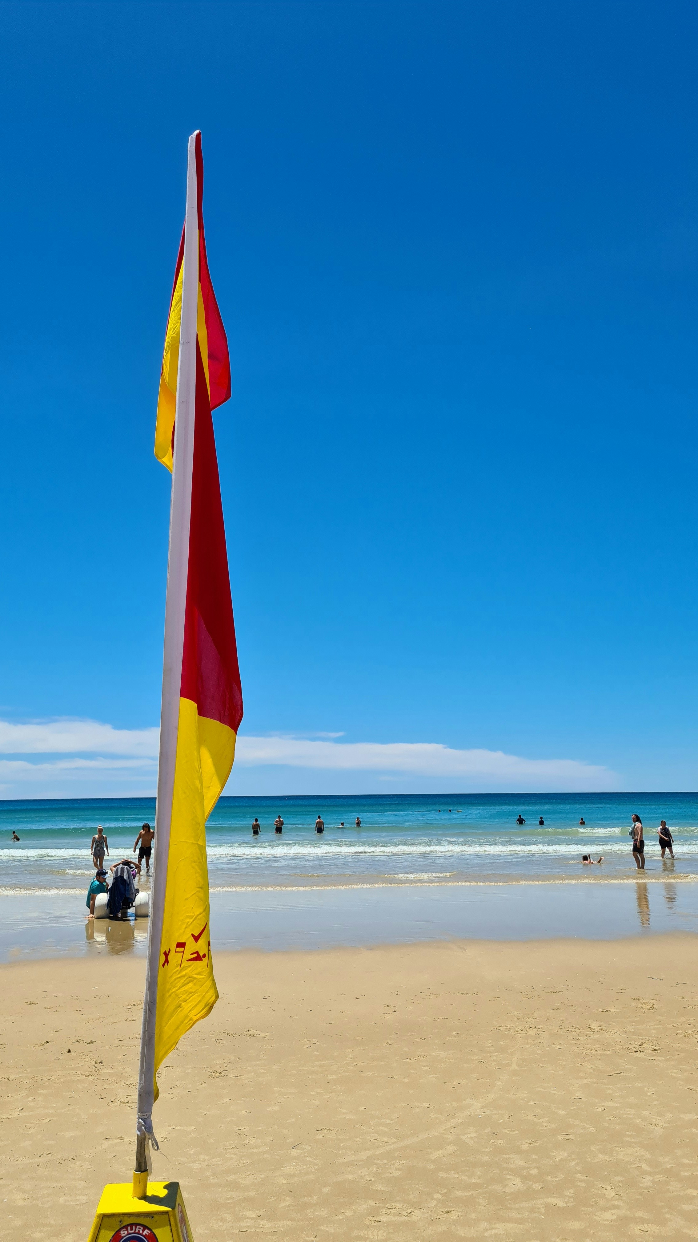 Red-Yellow Flagpole Standing Boldly Over a Sunlit Beach