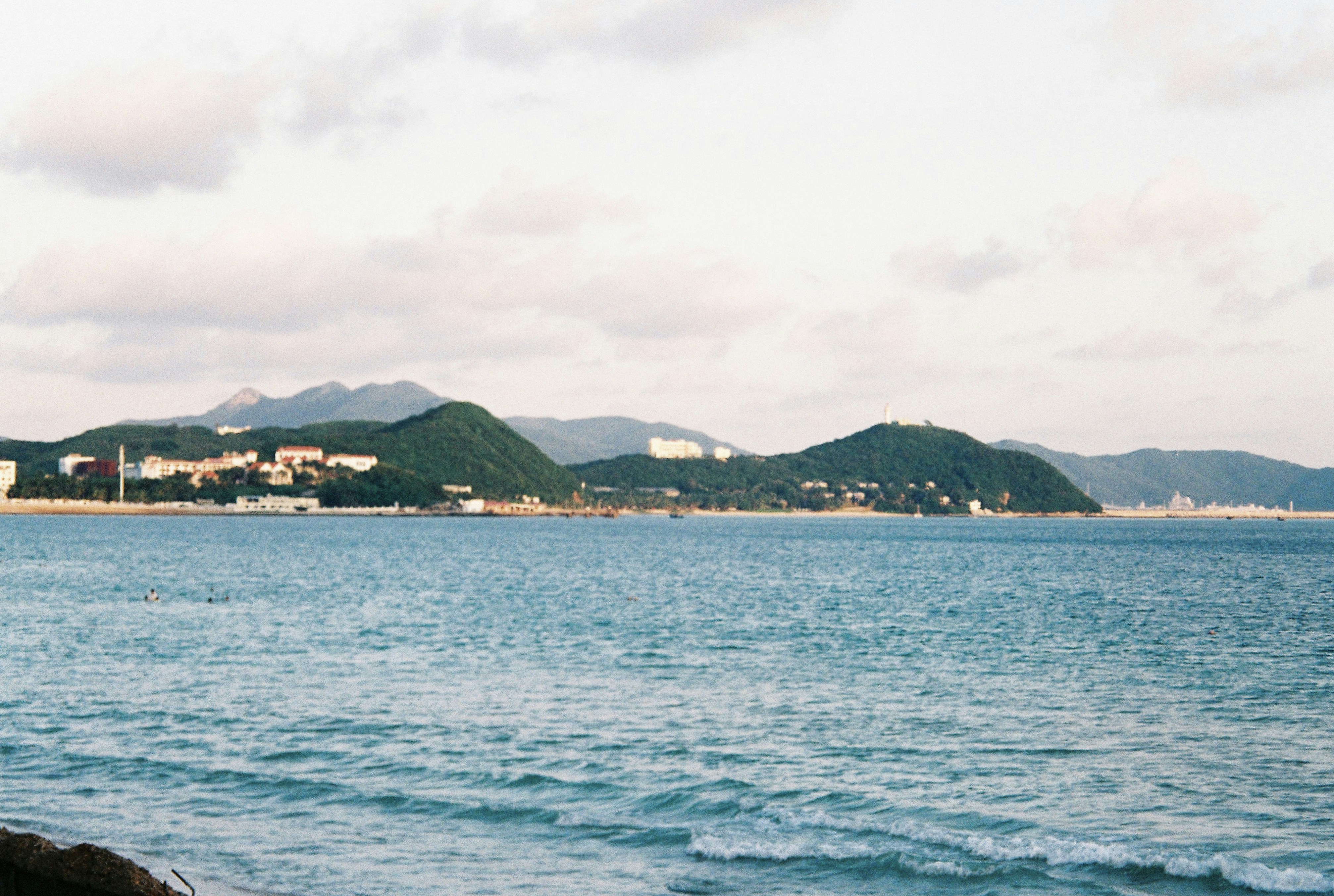 Serene coastal landscape featuring rolling hills and gentle waves under a pastel sky. The scene captures the tranquil essence of a seaside retreat.