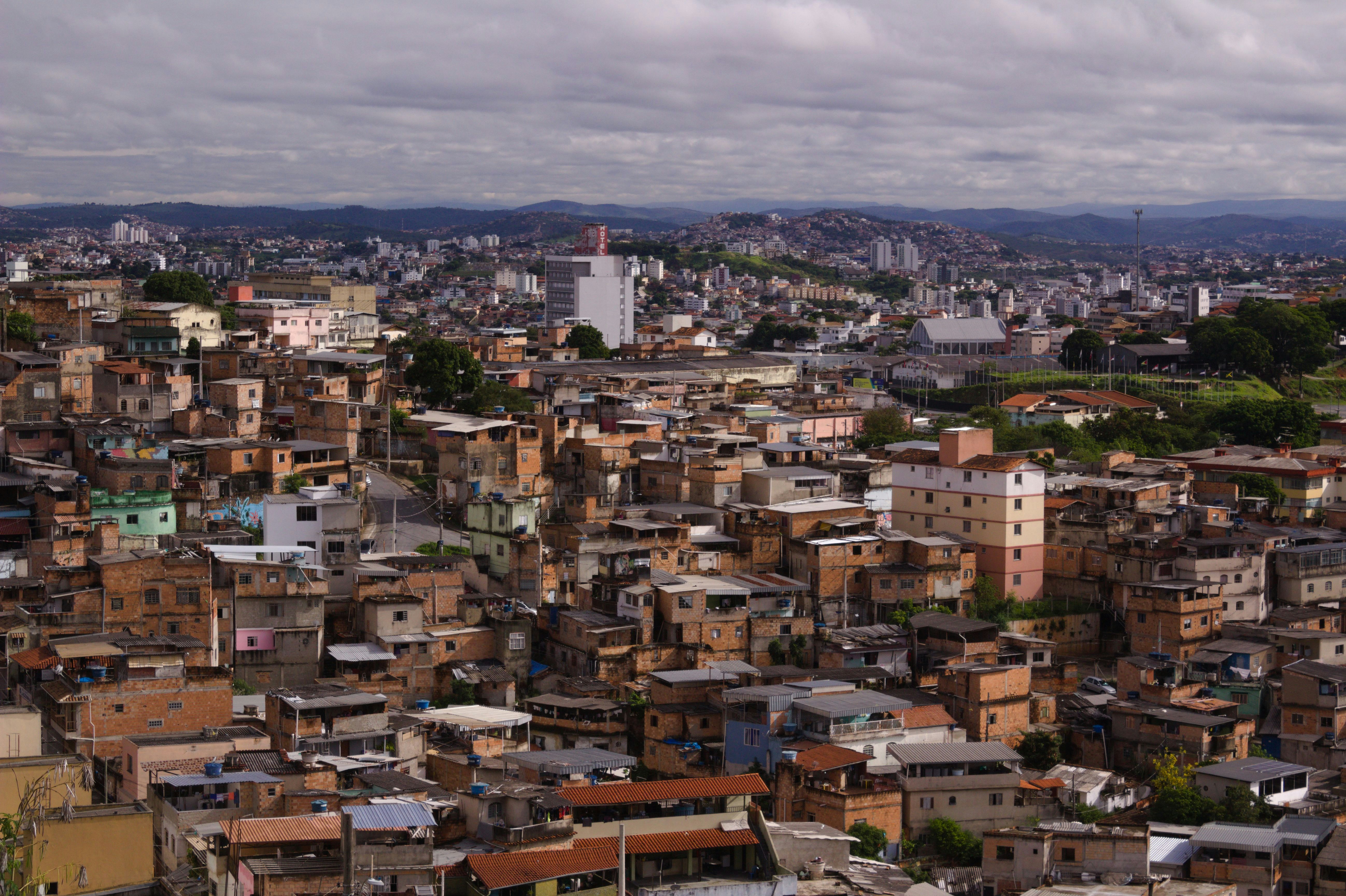 A panoramic view of densely packed urban housing, showcasing a vibrant community nestled amid rolling hills and cityscape in the background.