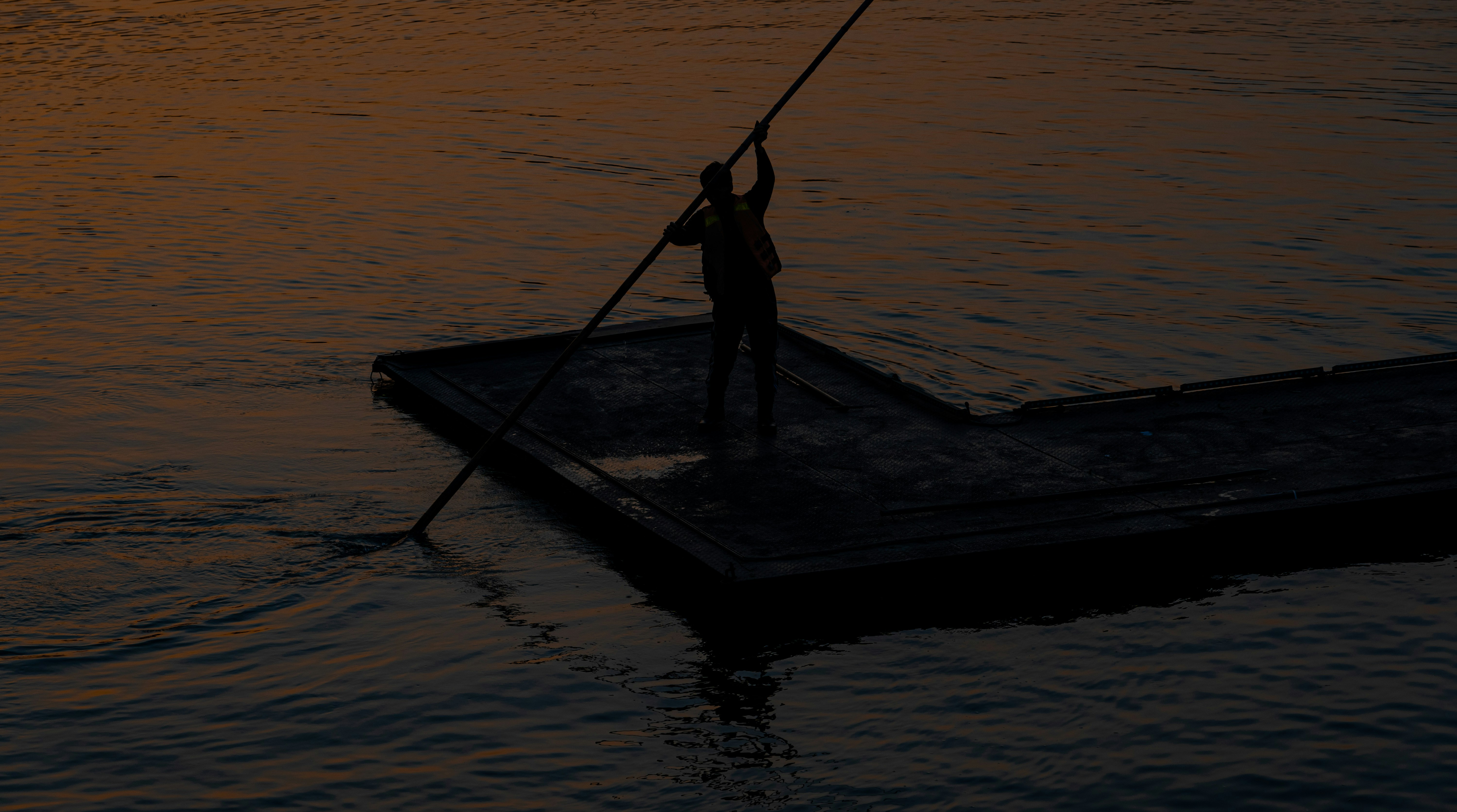 A man is standing on a raft in the water photo – Free Black Image on ...
