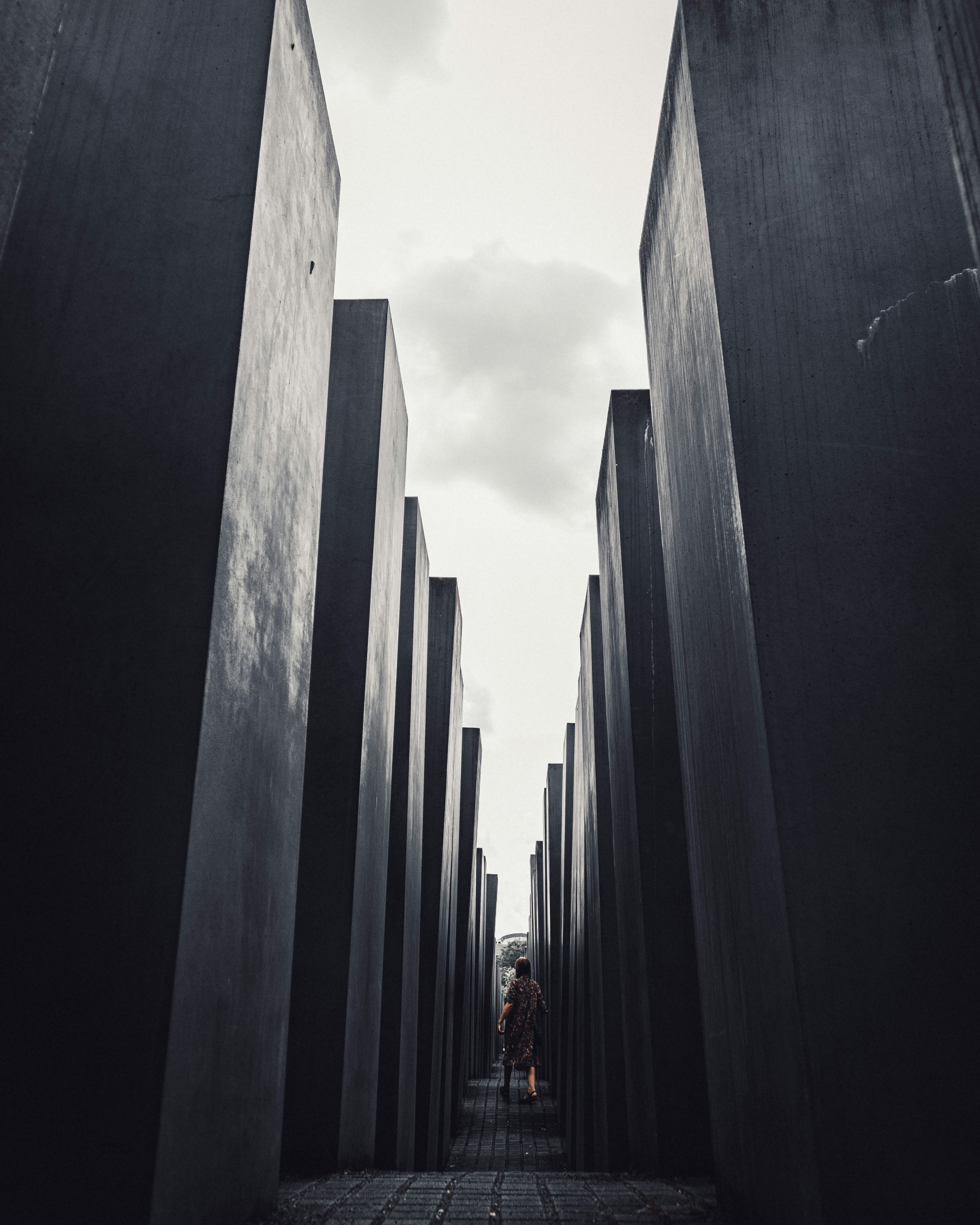 A person standing between two tall concrete structures photo – Free ...